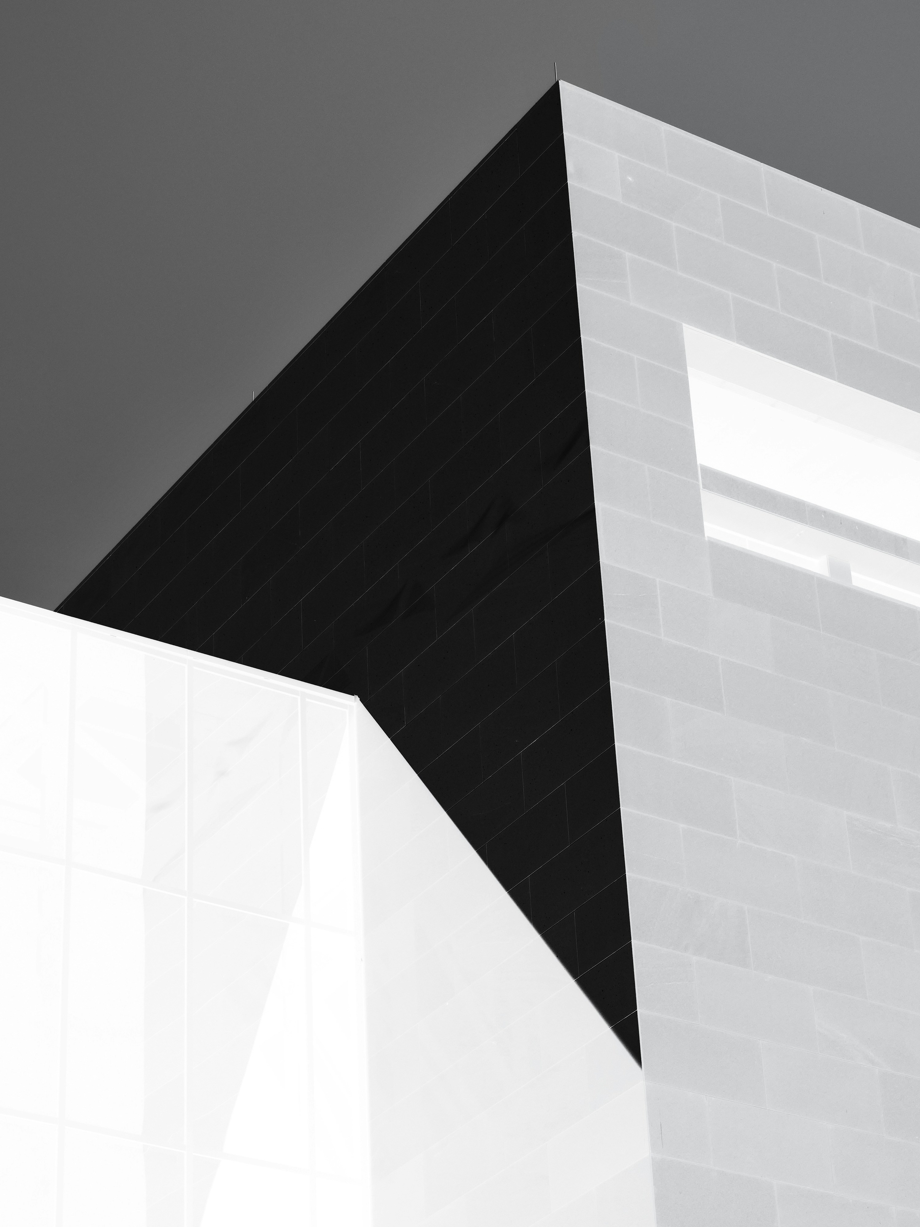 Monochrome architectural composition emphasizing sharp geometric planes and contrasting textures.