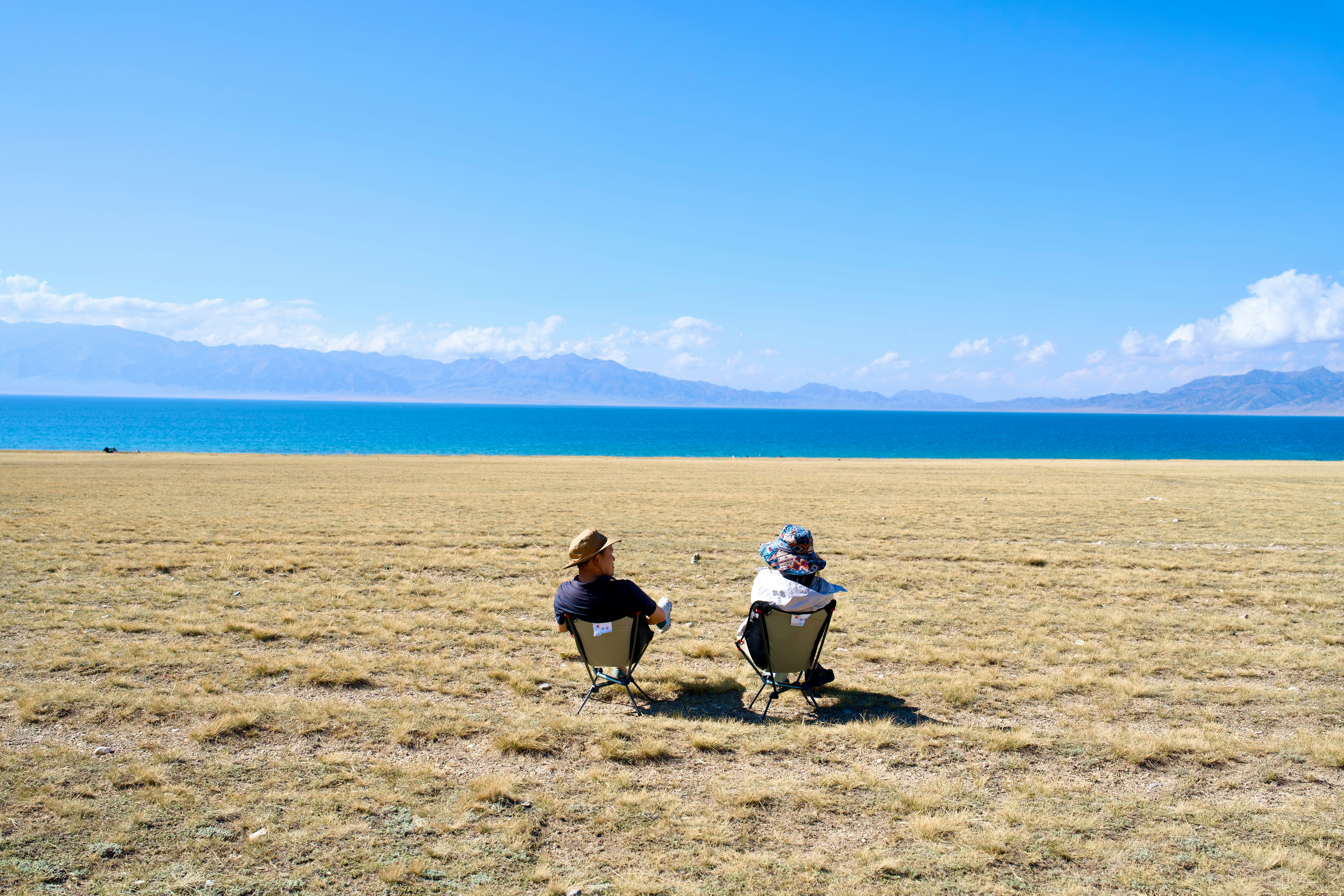 Two loungers under a boundless blue sky by a salt-flat shore