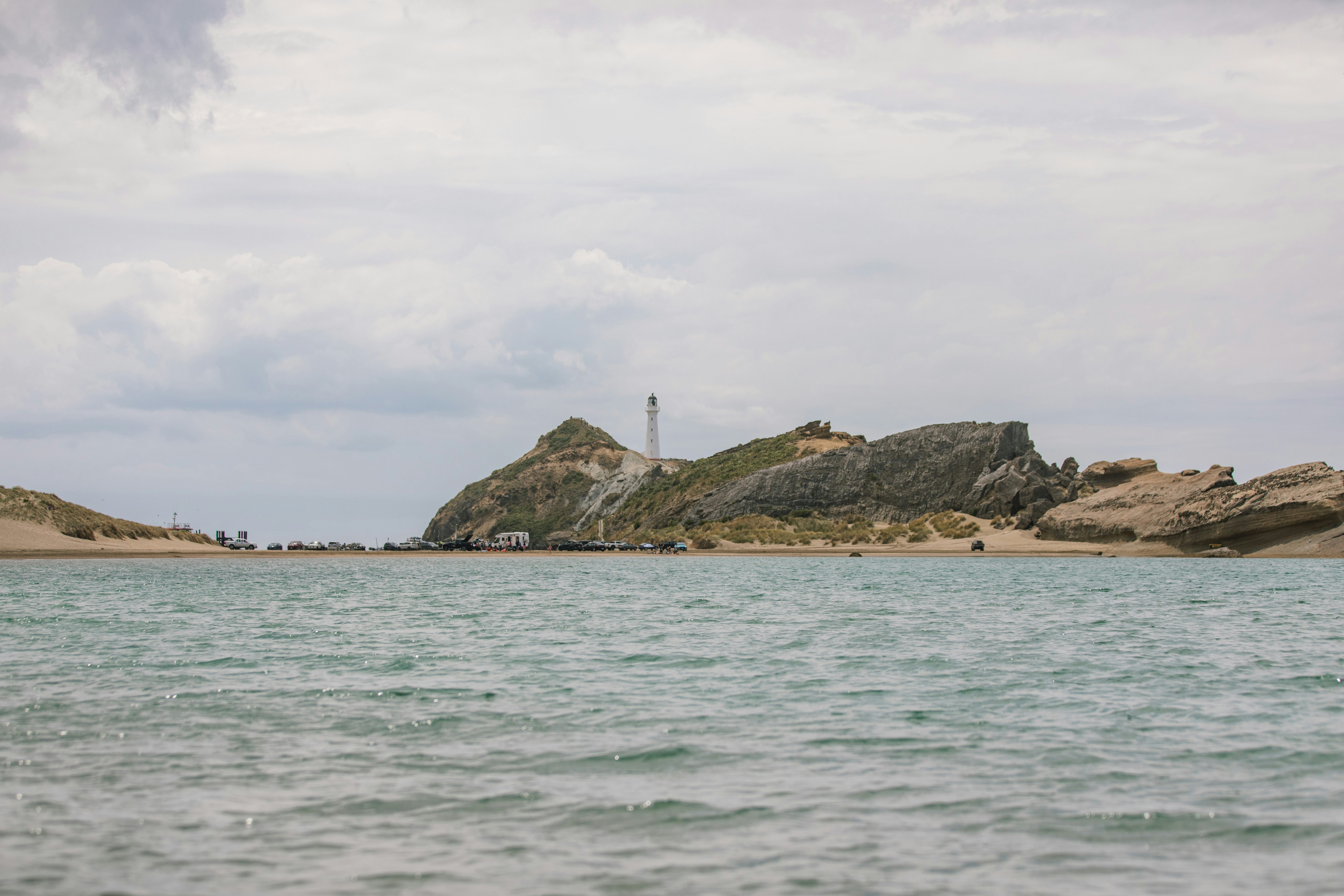 Lighthouse Crowned by Rocky Outcrop Across Gentle Toward-Horizon Sea