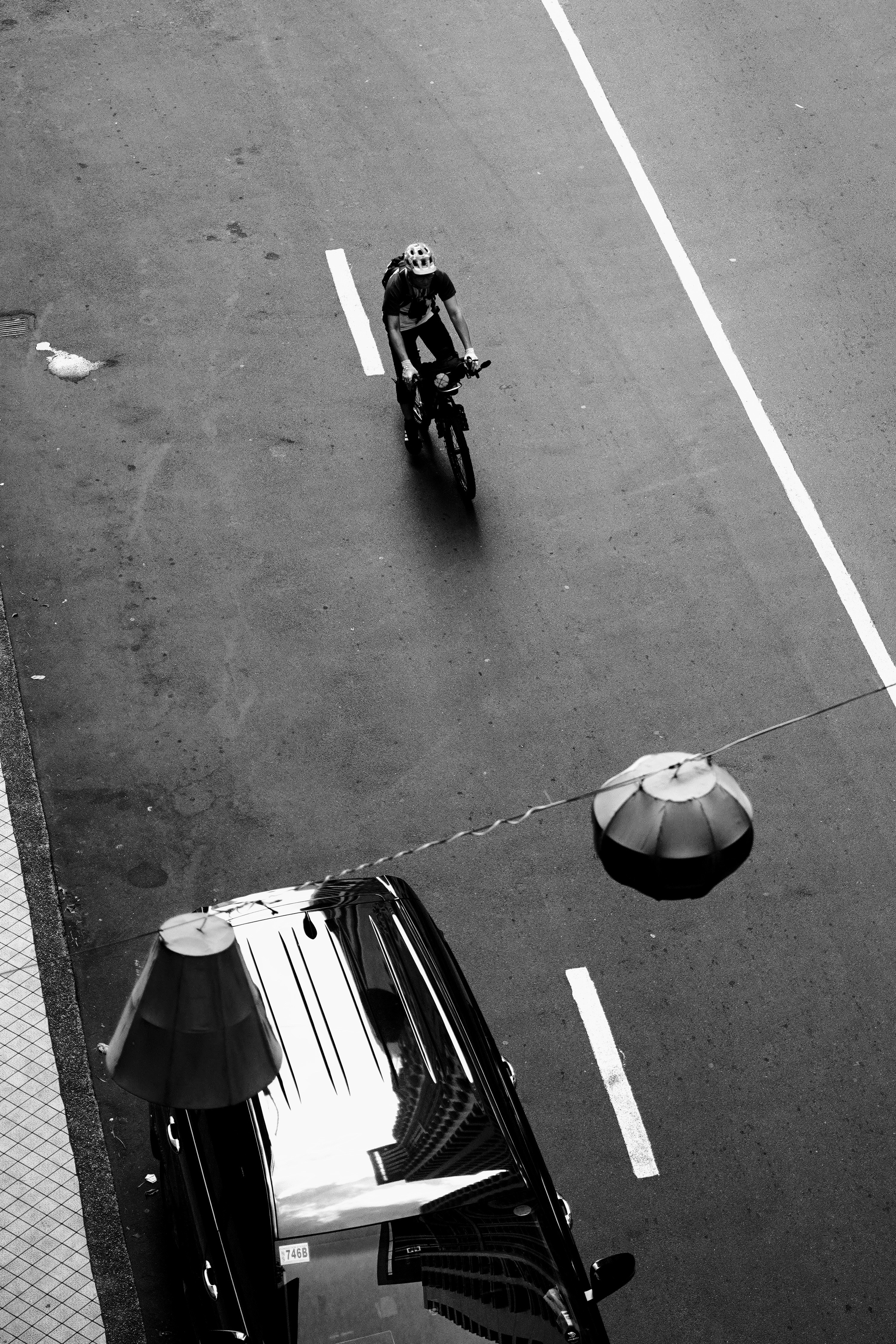 Alone in the Street: A Cyclist beneath a Suspended Umbrella