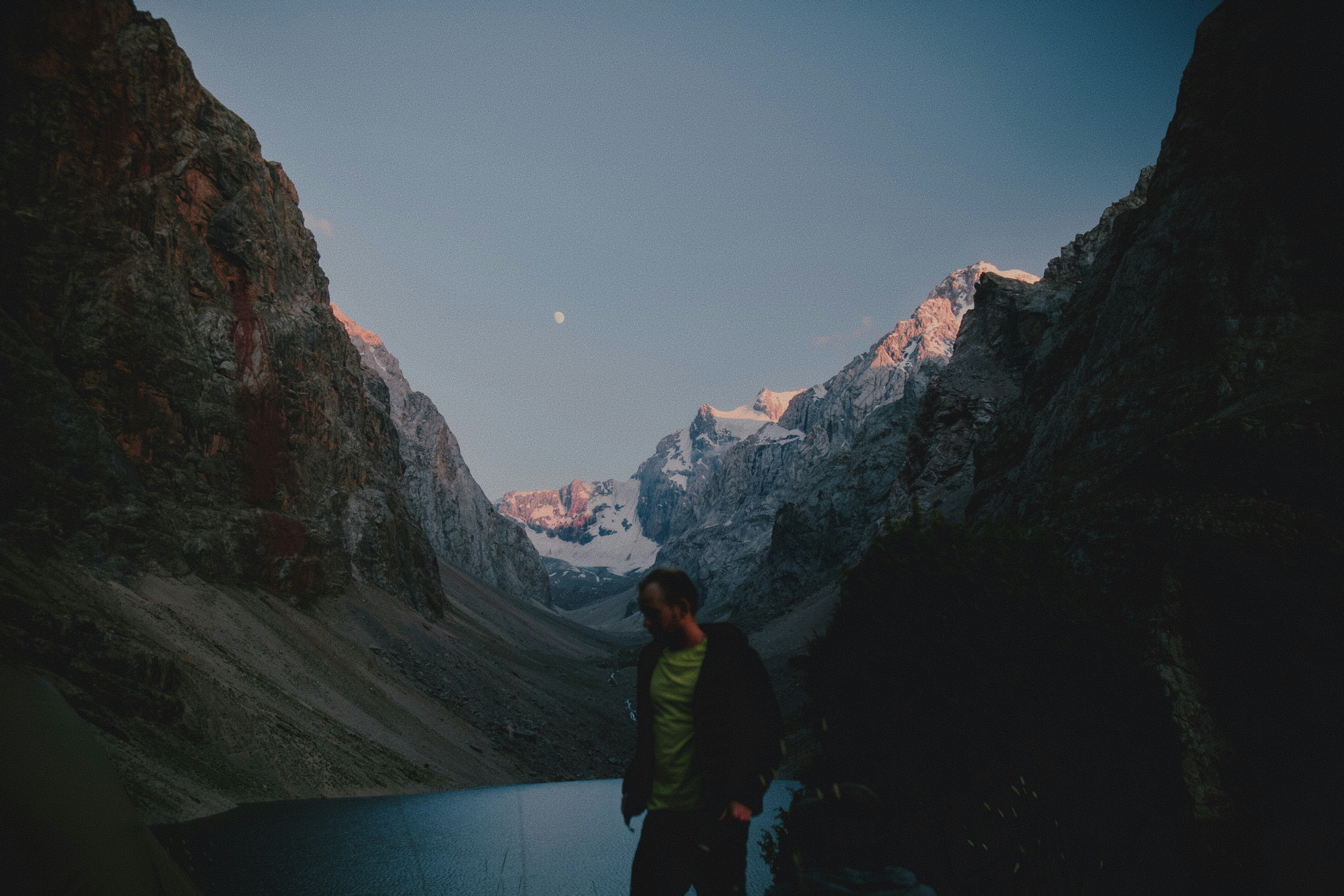 Traveler in a Twilight Basin Beneath Snow-Capped Peaks
