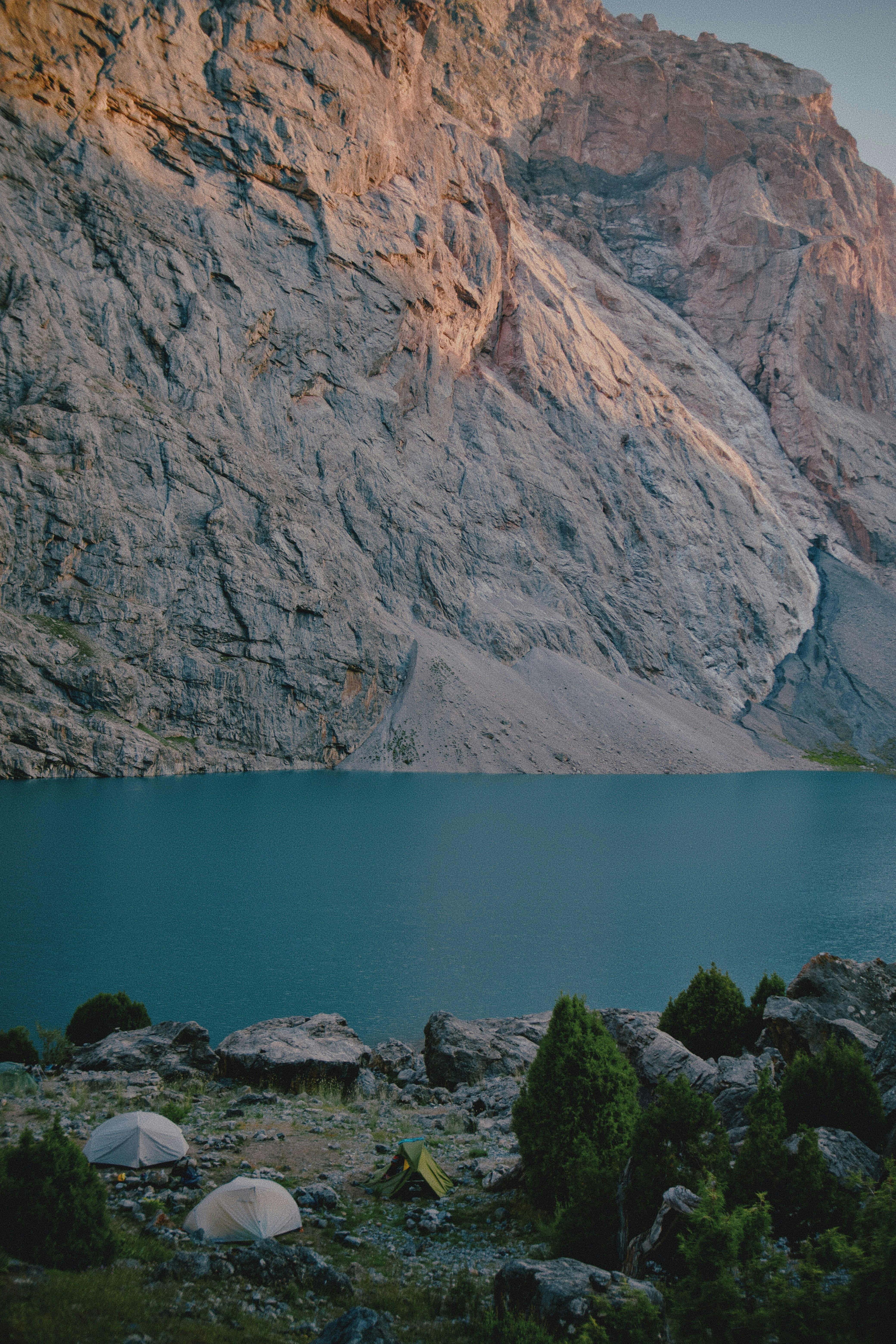 Azure Mirror: Campers at the Foot of a Rugged Alpine Wall