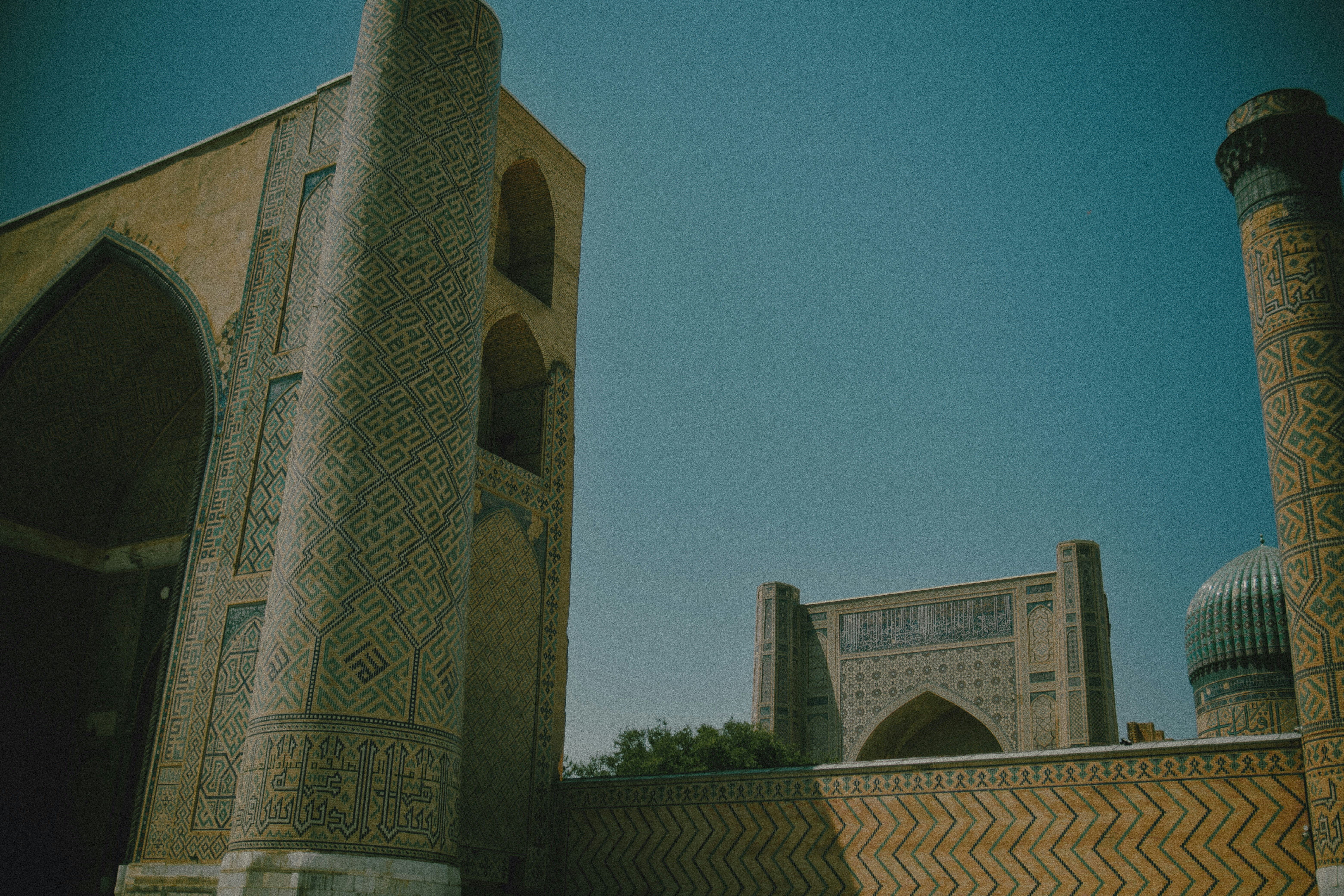 Sunlit Courtyard: Persian-style Architecture with Tilework and Domed Minarets