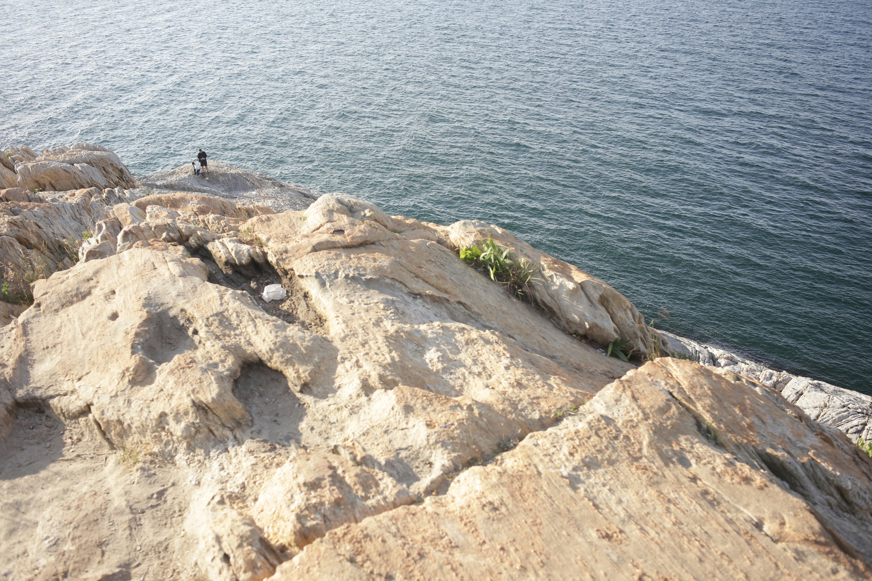Edge of the Ocean: Lone Figure on Sunlit Granite