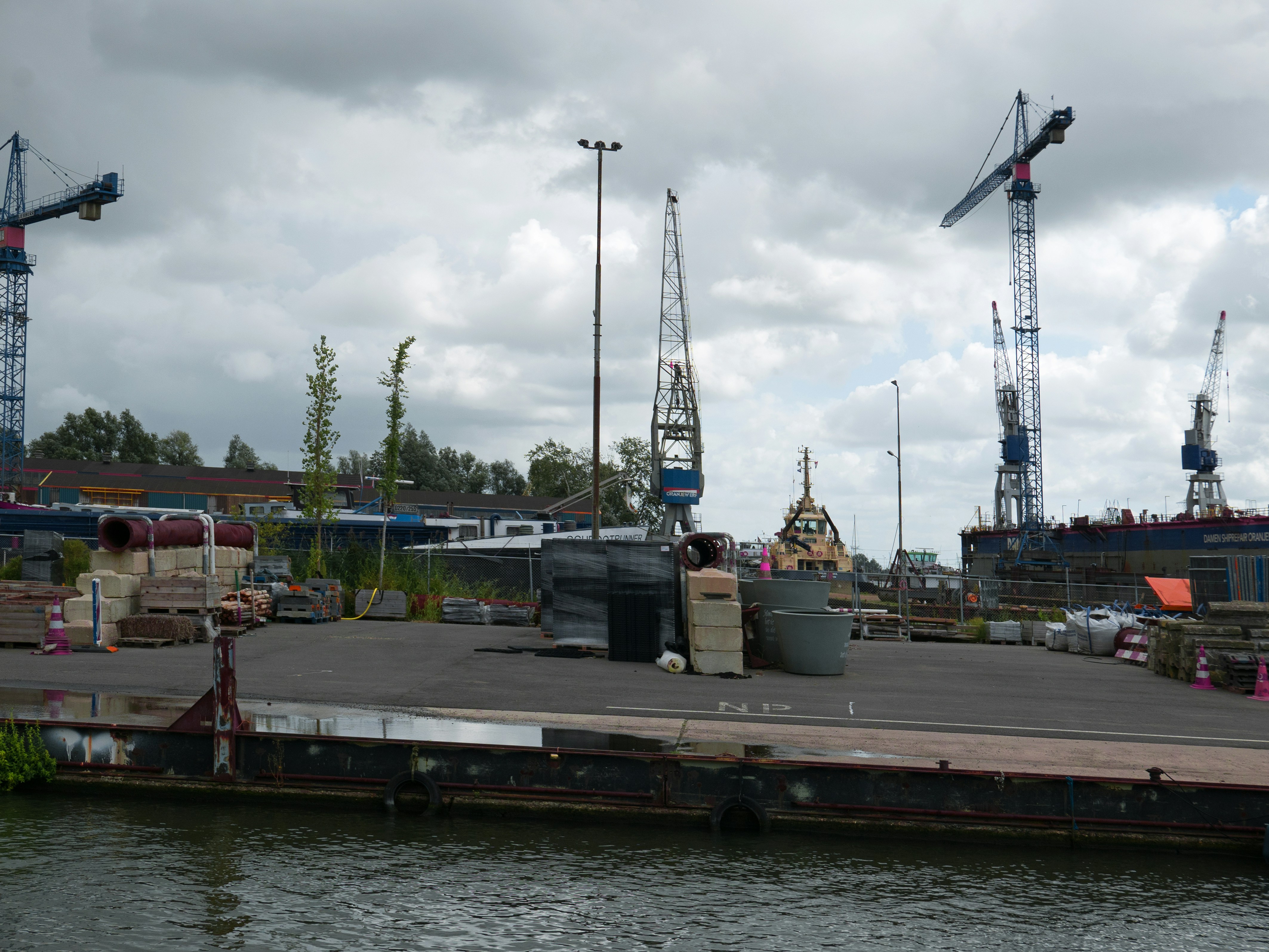 Industrial Harbor in Motion: Cranes, Water, and a Distant Carnival