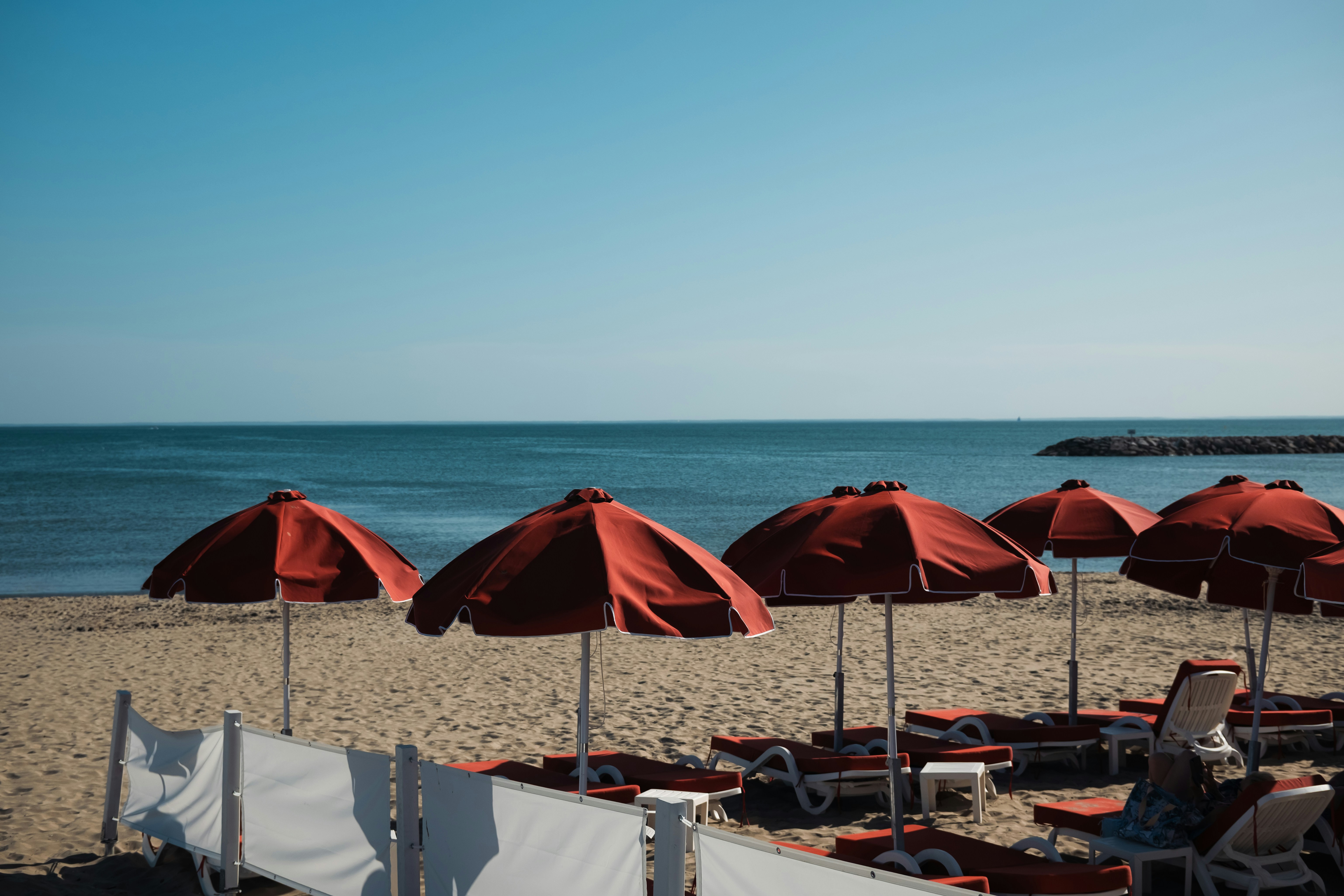 Red Canopy Row: A Quiet Beachfront Retreat under a Clear Sky
