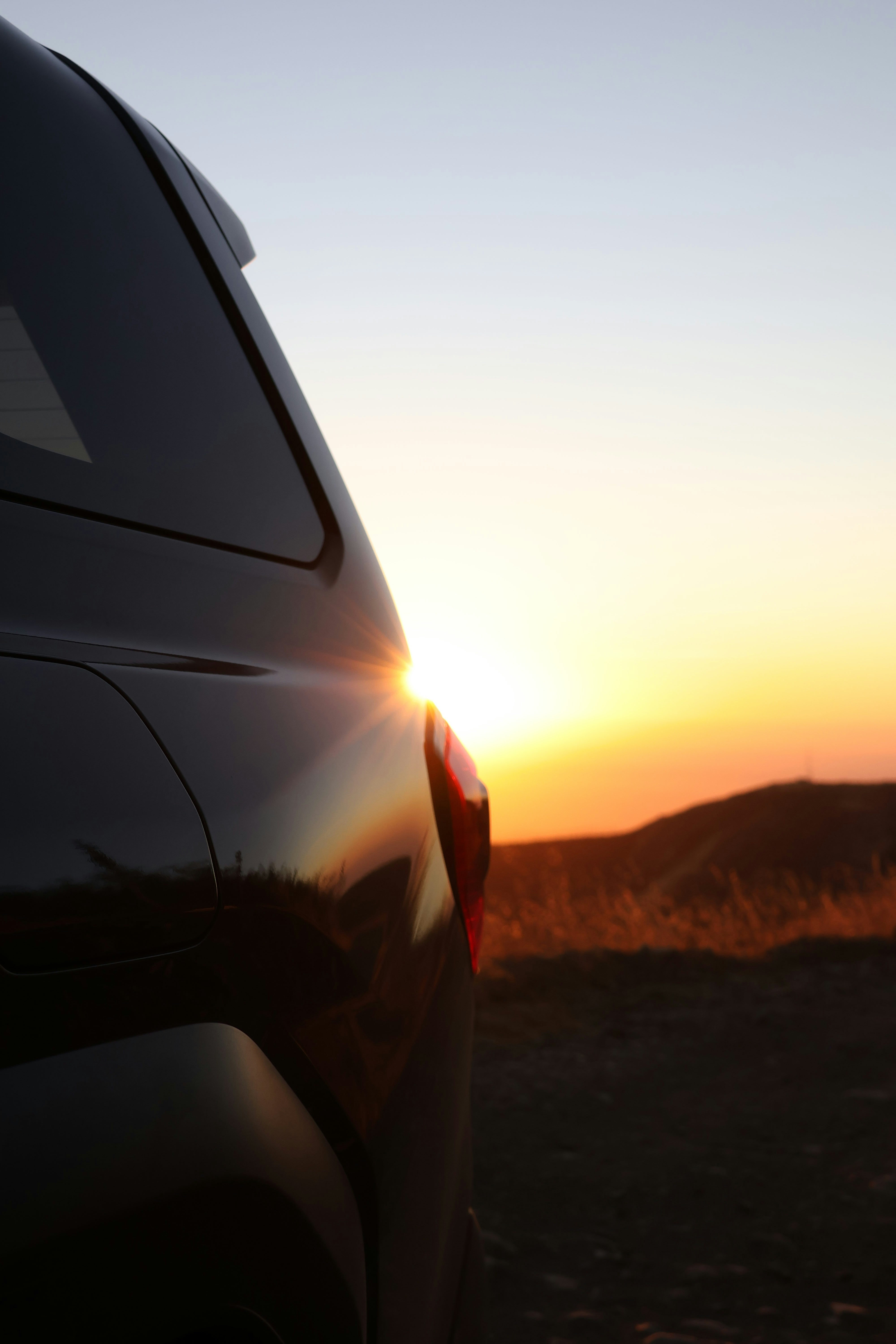 Sunlit tailgate: the road to dusk beside a glossy car