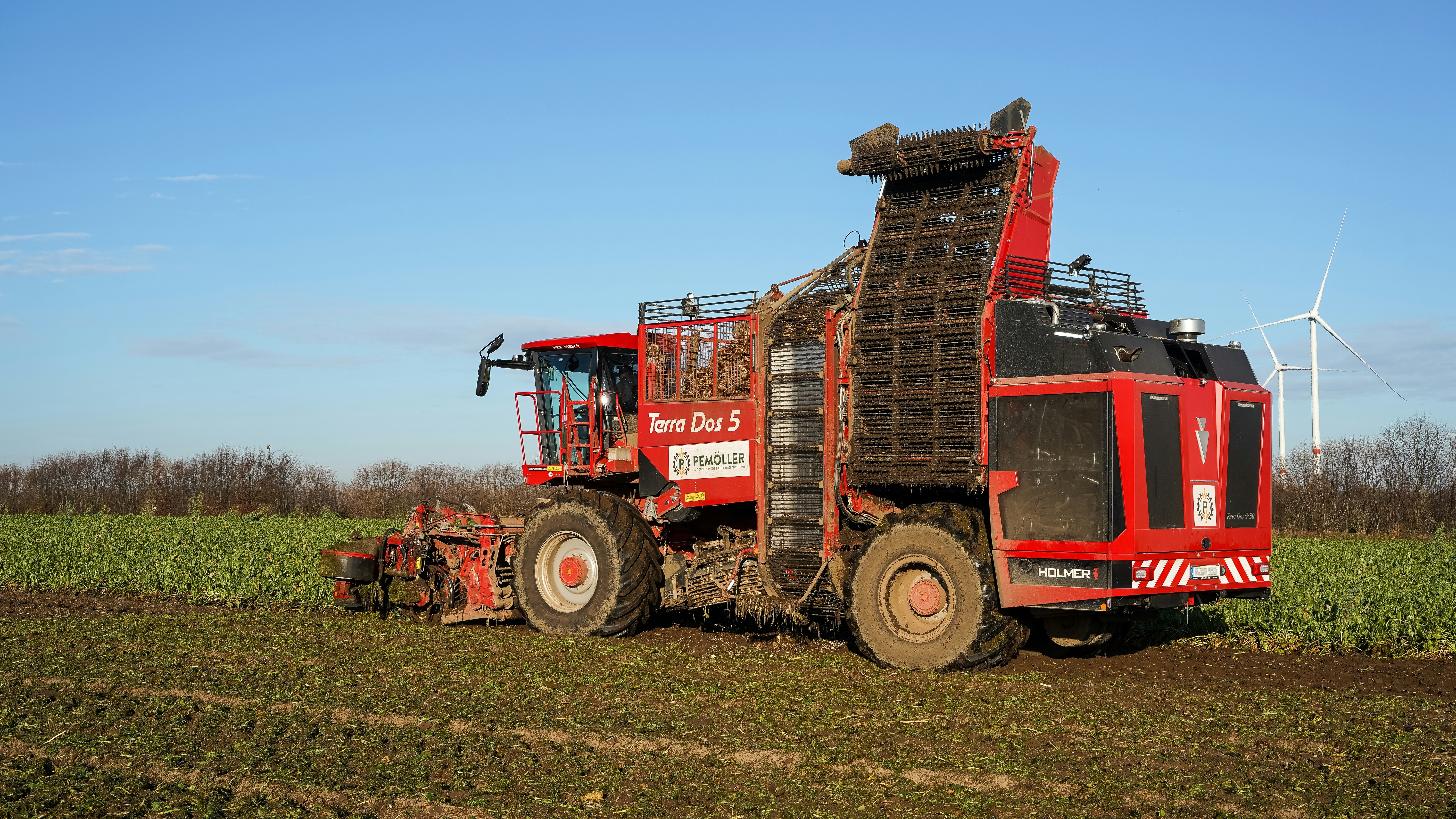 Red Harvester Resting in a Plowed Field beneath Clear Skies