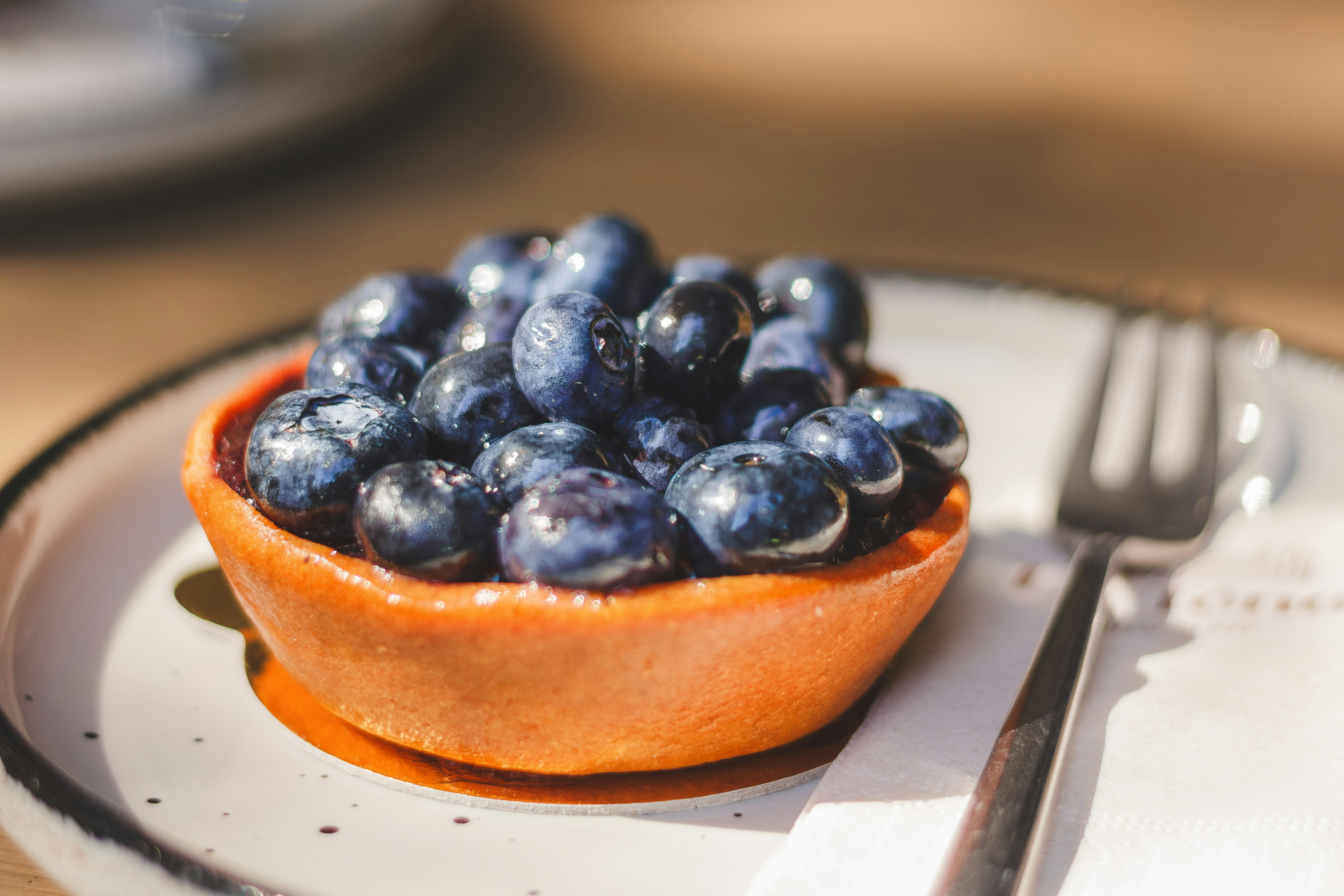 Blueberry Crown: A Golden Tart Nestled on White Plate