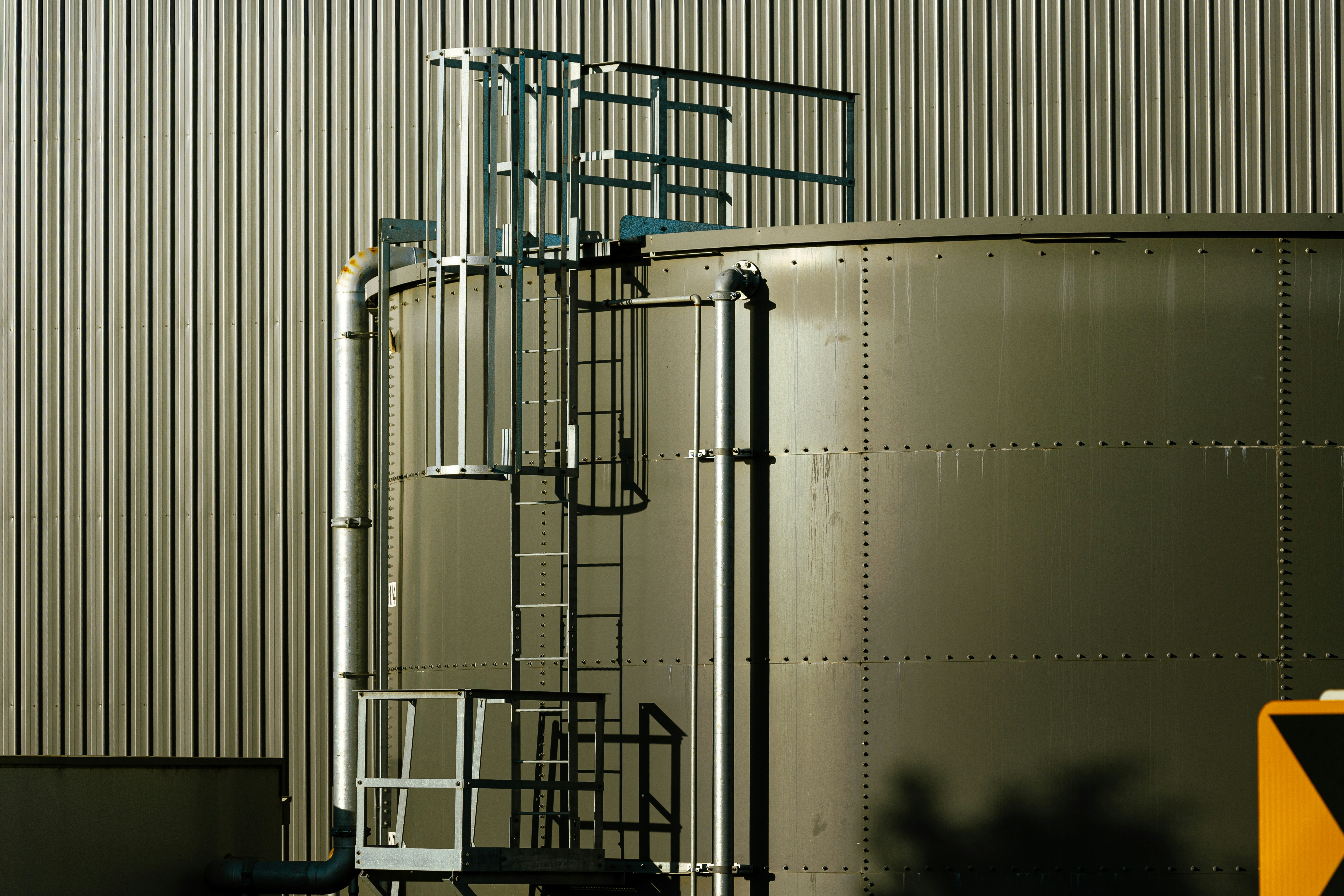 Industrial Silhouette: A Metal Staircase Clings to a Creamy Cylinder