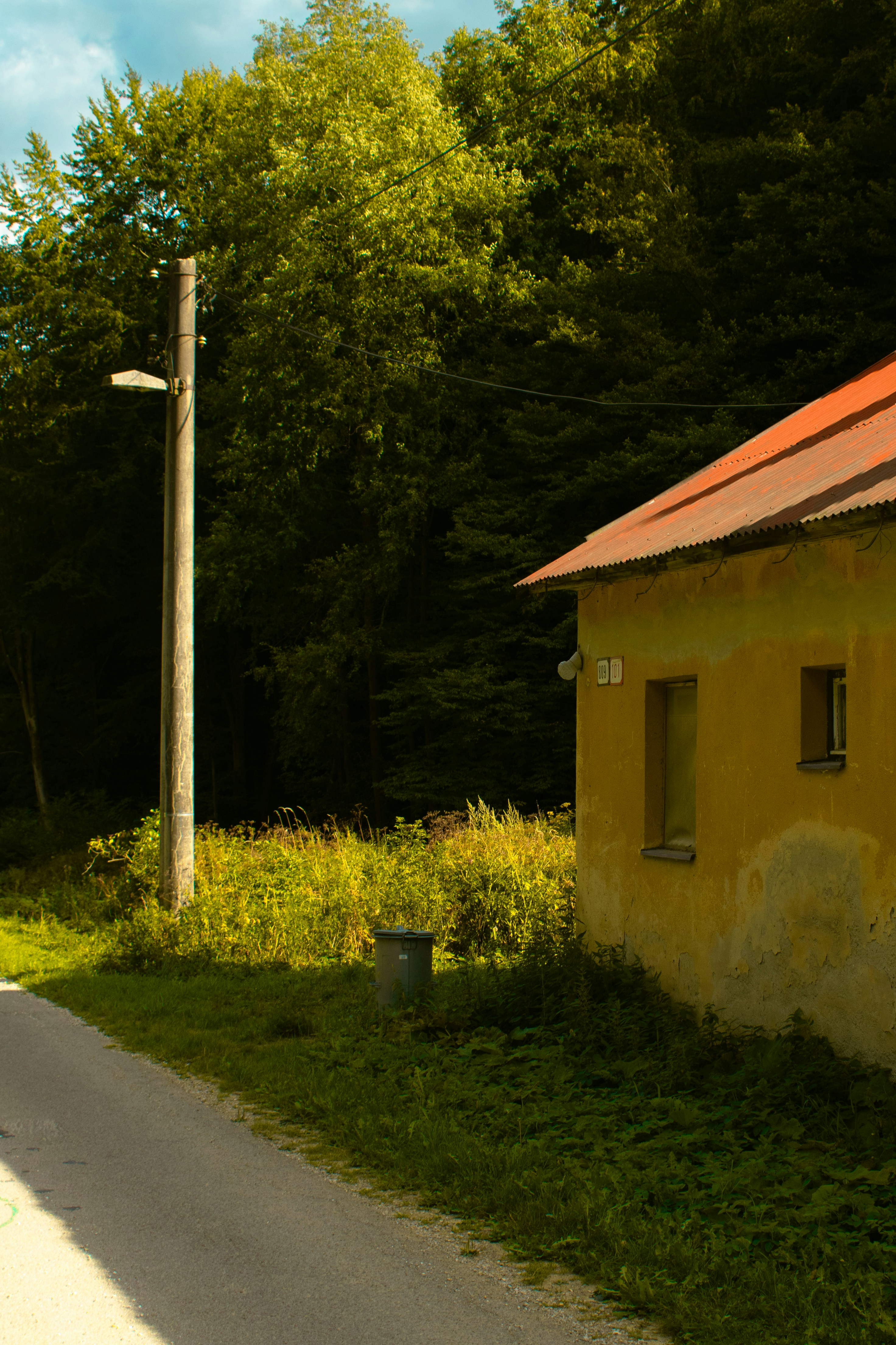 Rural Moody Light Falls on Weathered Yellow House by the Road