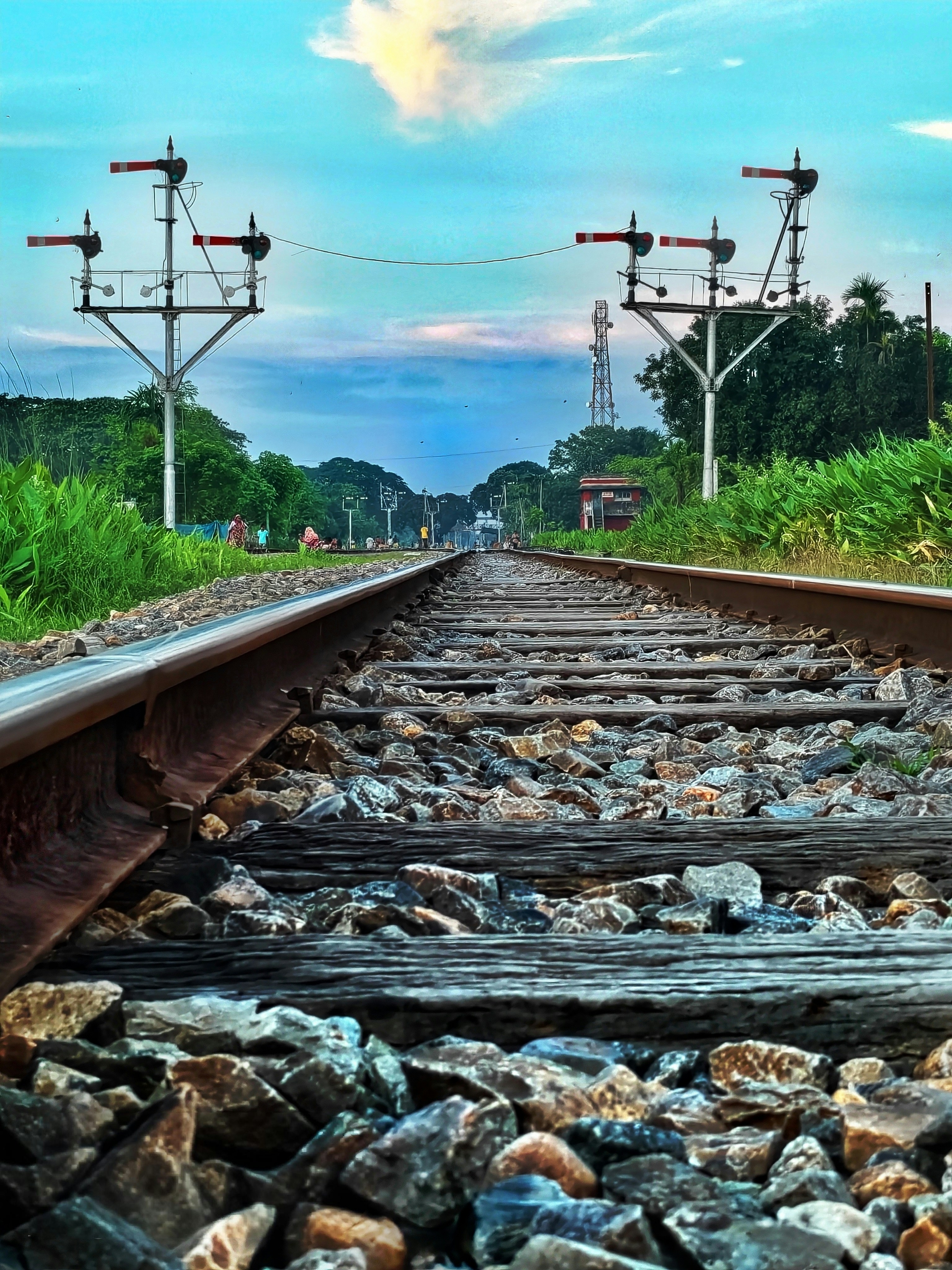 Railway tracks stretching into the distance under a bright blue sky with signal arms