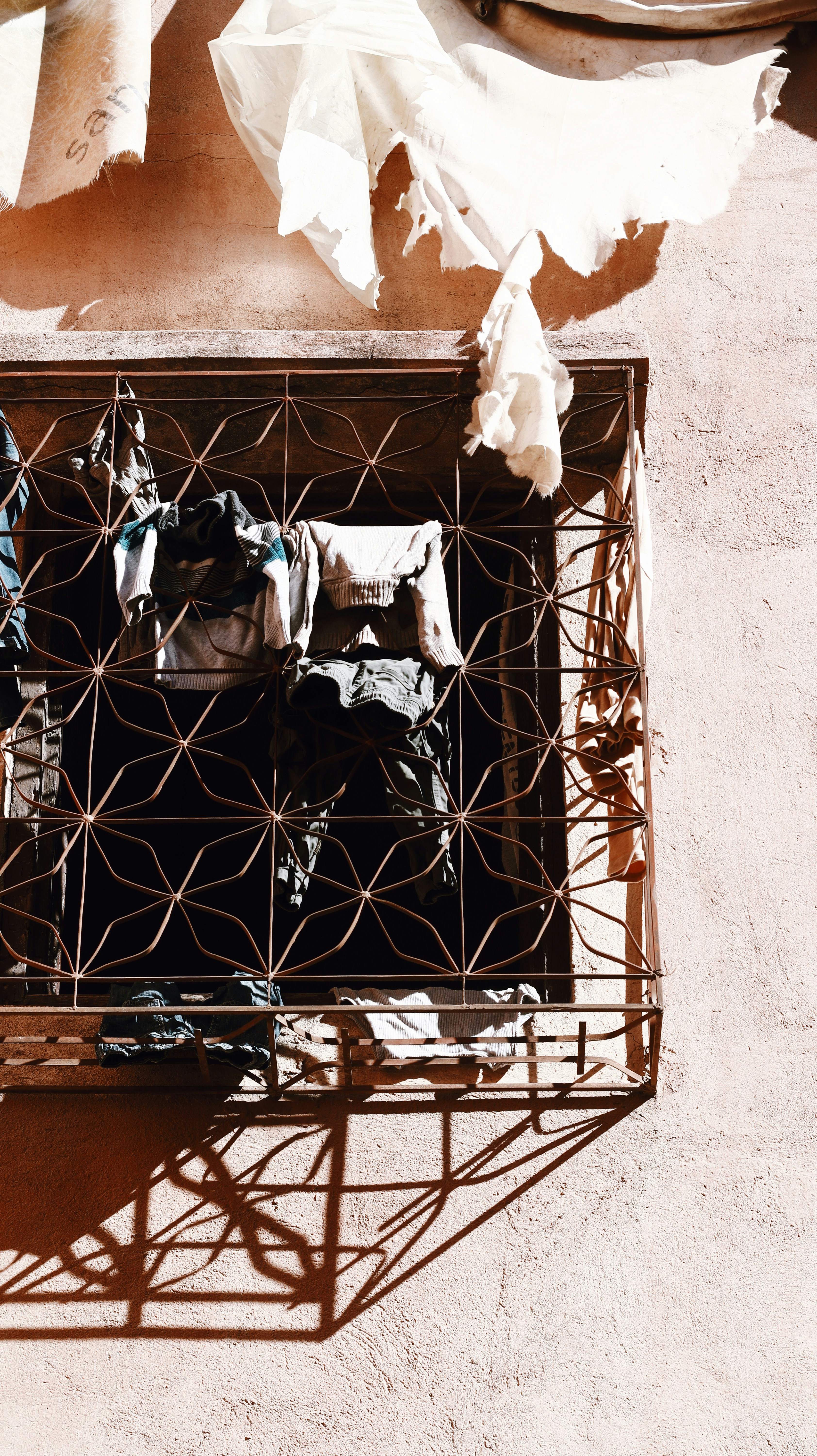 Laundry Grid: Clothes Caught in Sunlit Ironwork