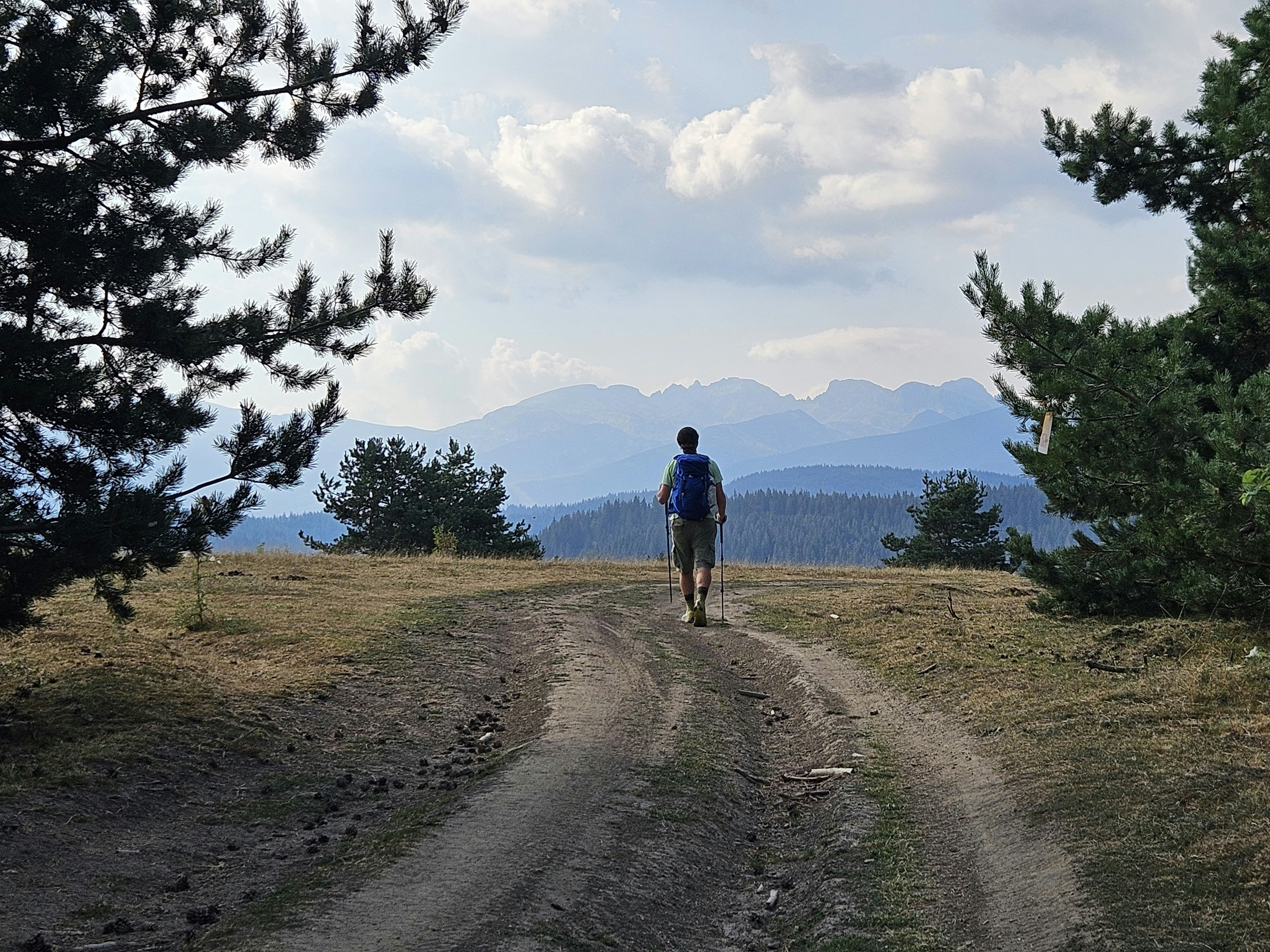 Trailbound silhouette: climber threading a sunlit ridge toward distant peaks
