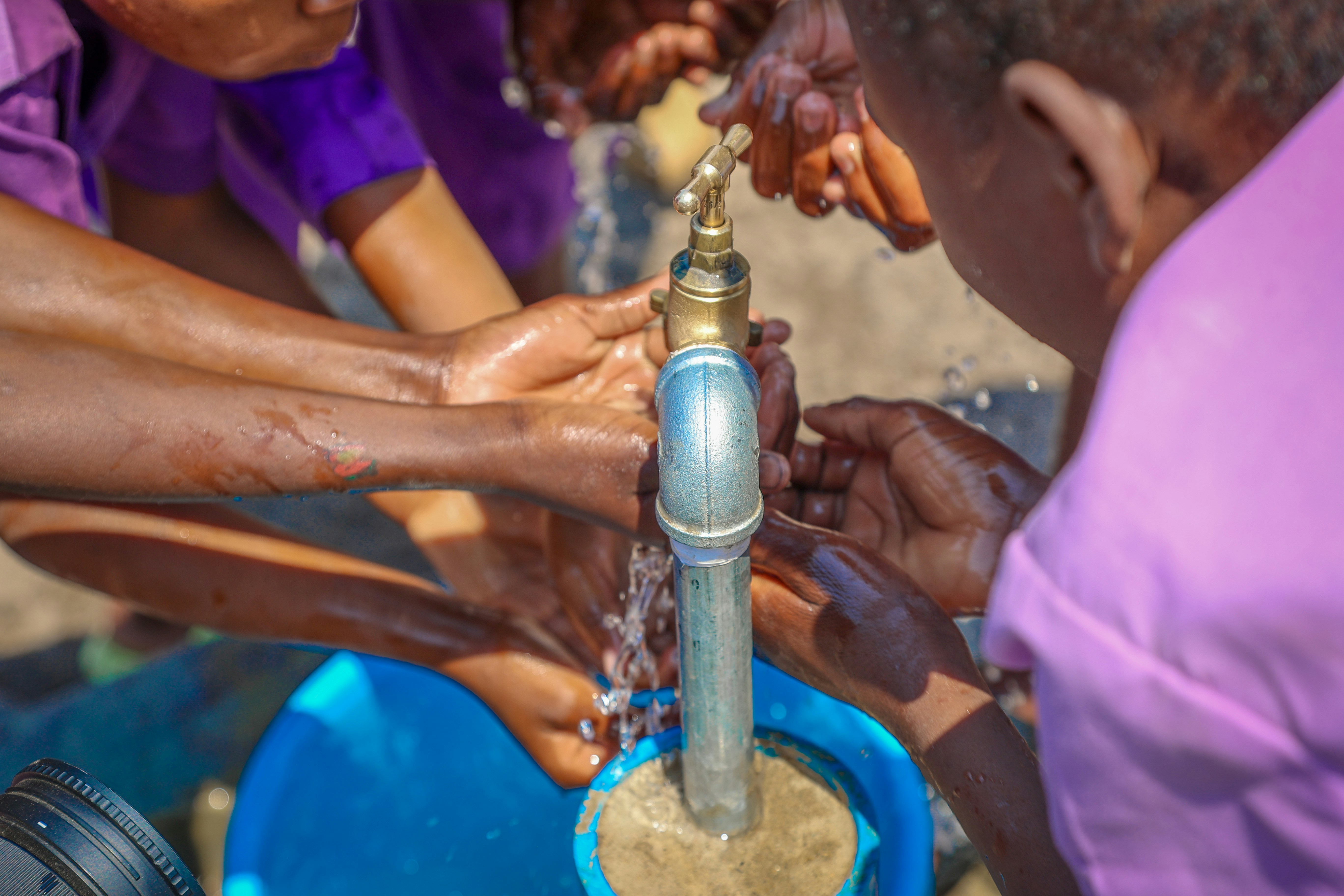 Hands Under Pressure: Youths Dial In Water at a Central Tap