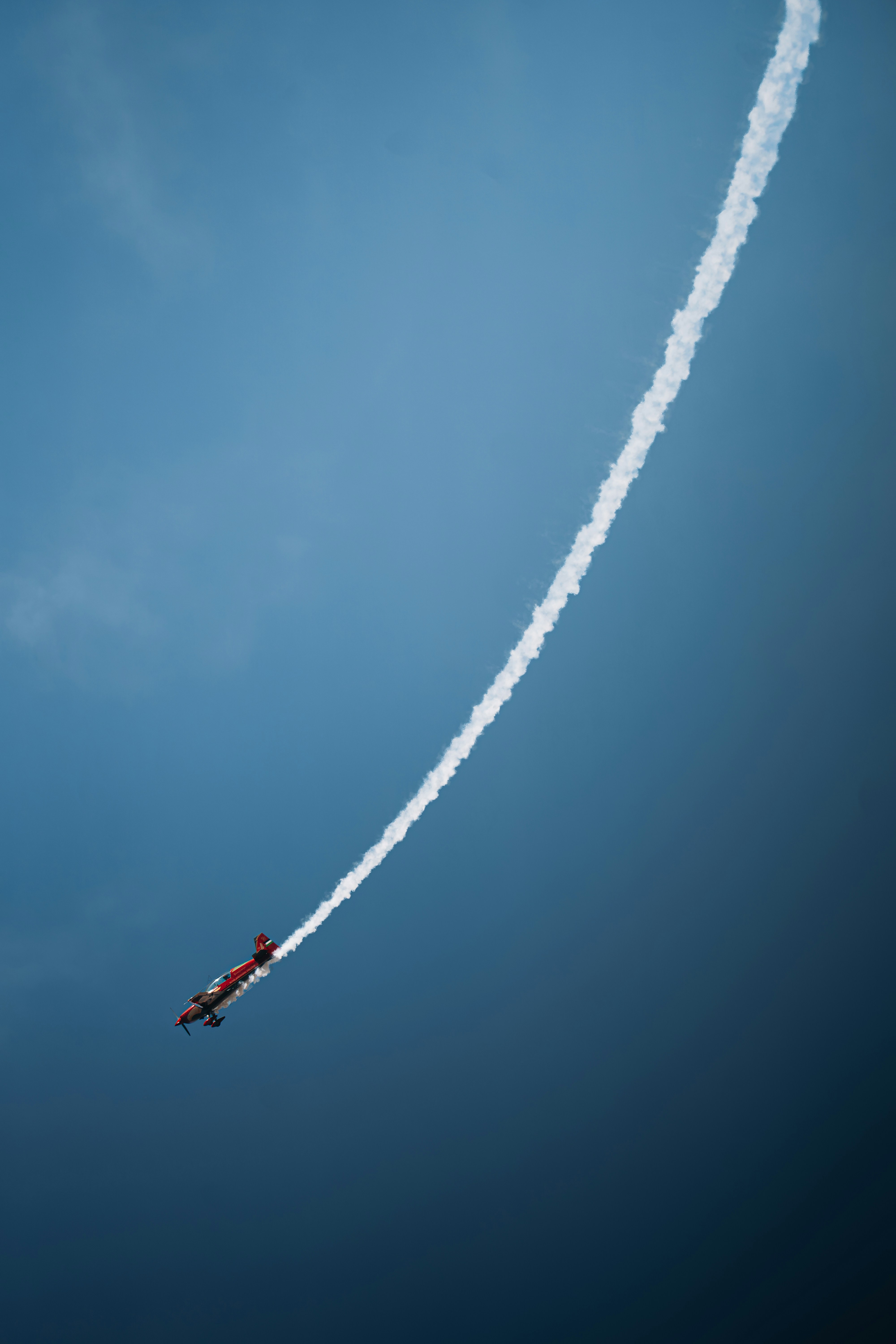 Trail of Smoke: A Solo Aerobatic Biplane Arcs Across a Cobalt Sky
