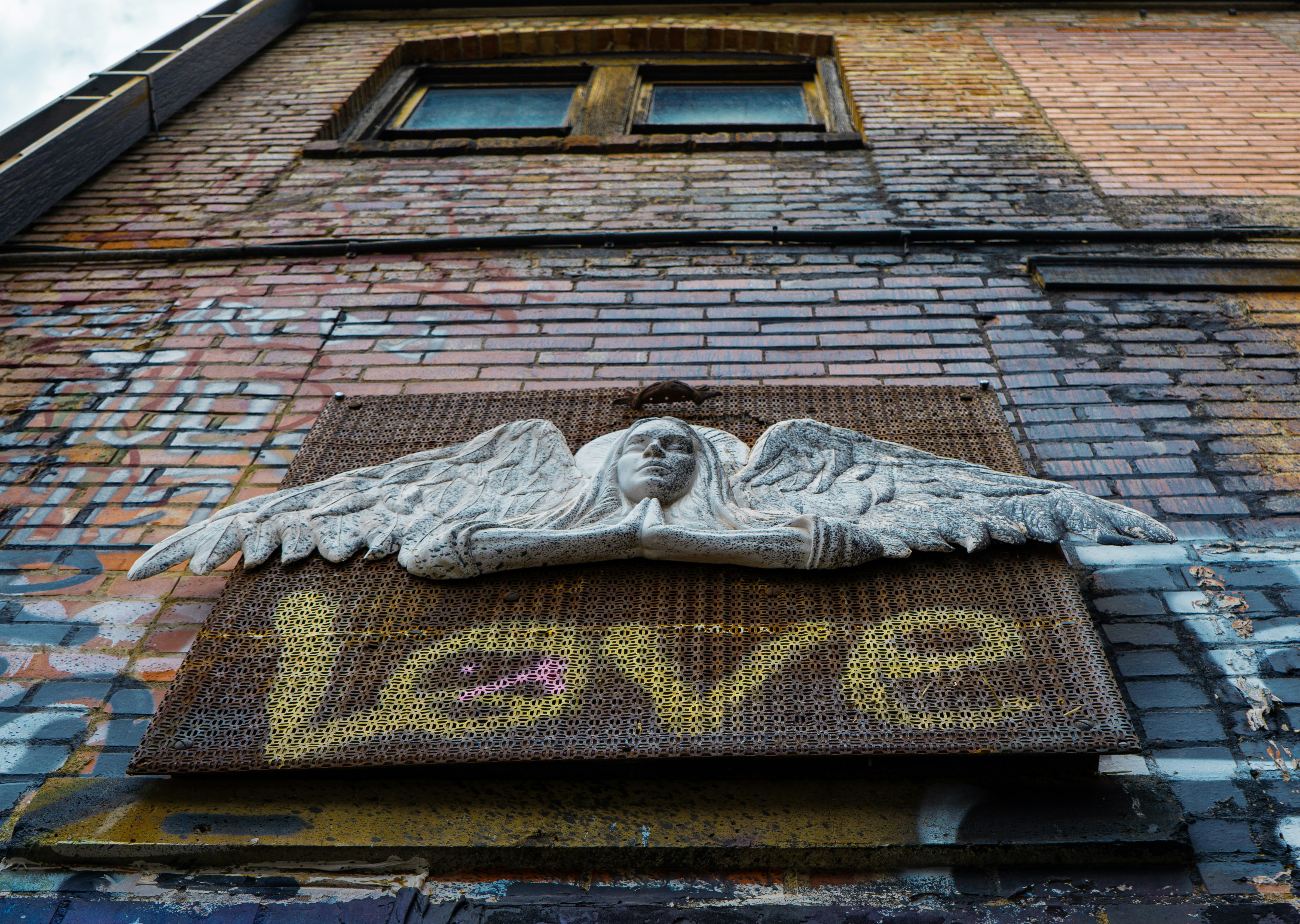 Weathered Angel Sign Above a Faded Love Graffiti