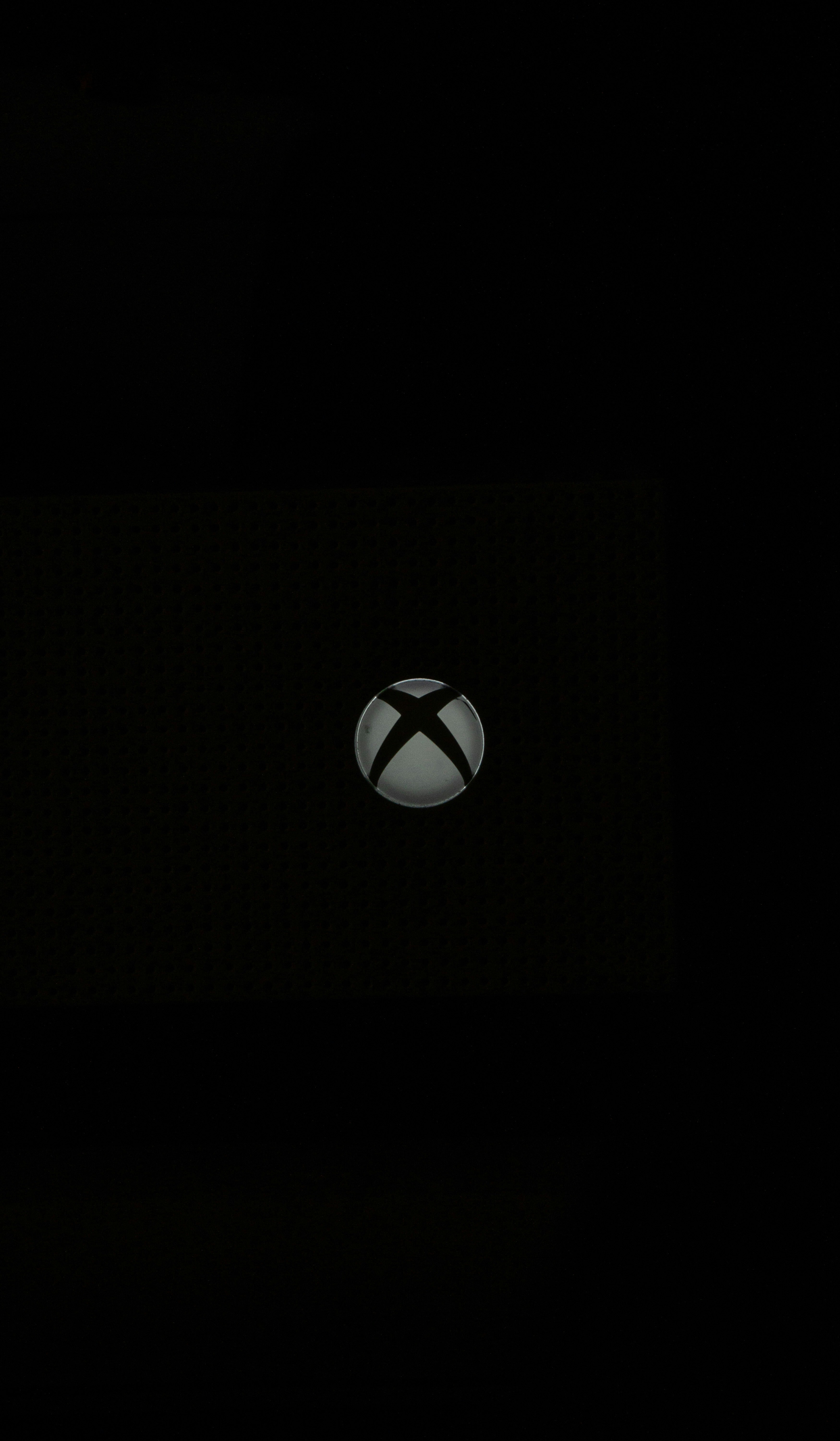 Xbox logo glow on a dark surface: a solitary emblem in shadow