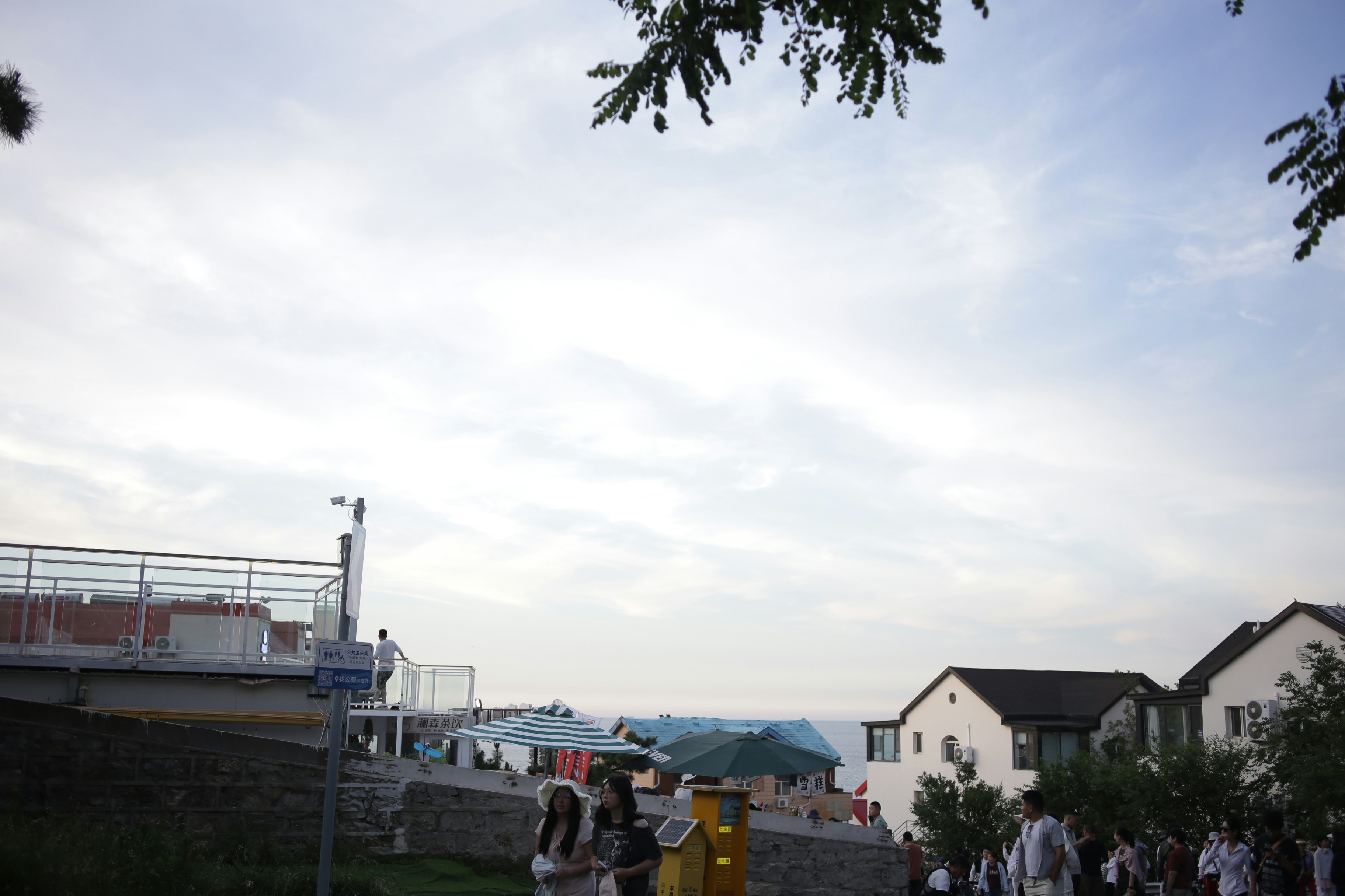 Coastal Boardwalk at Dusk: People Gather by the Sea