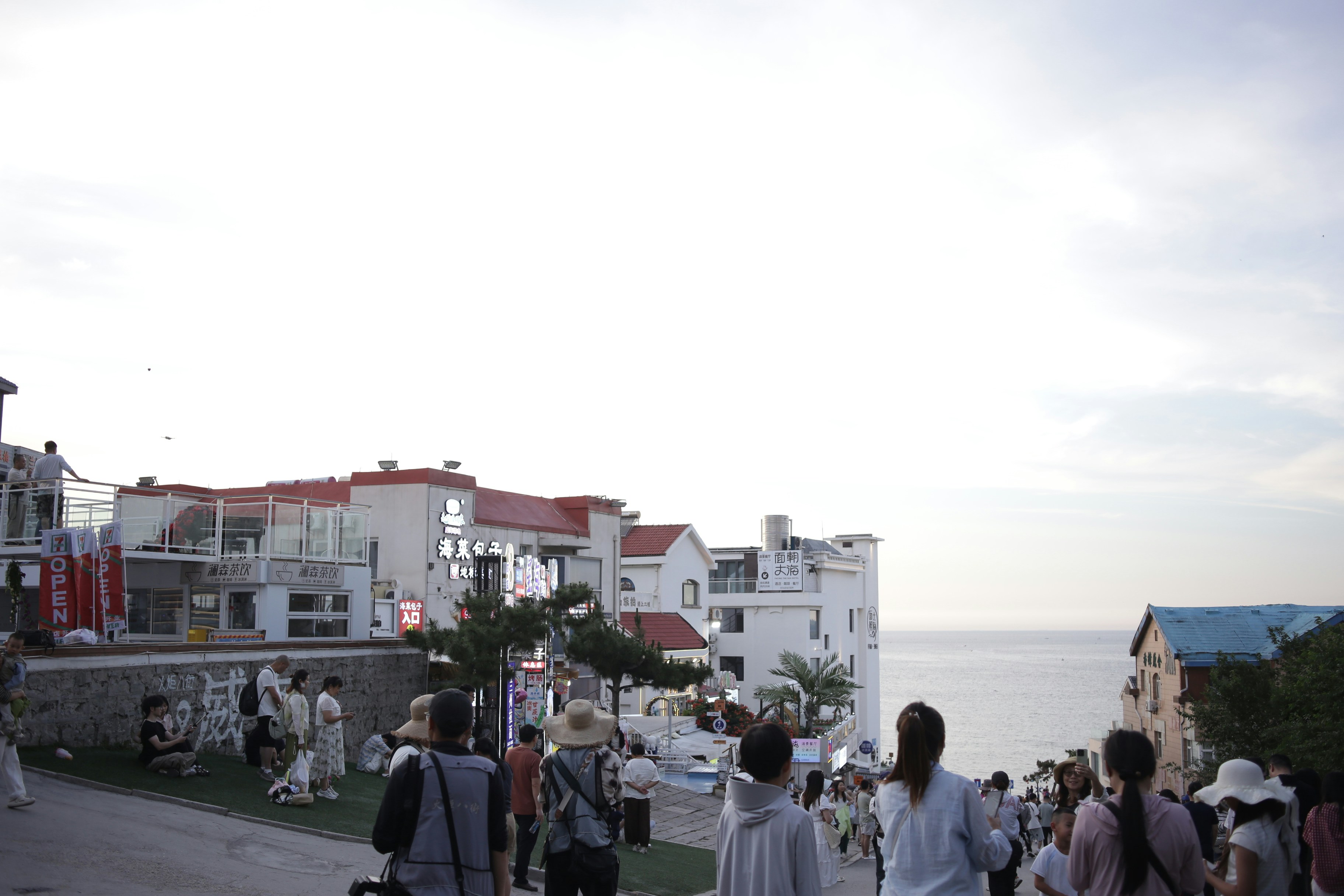 Sunlit seaside plaza teeming with visitors and pastel buildings