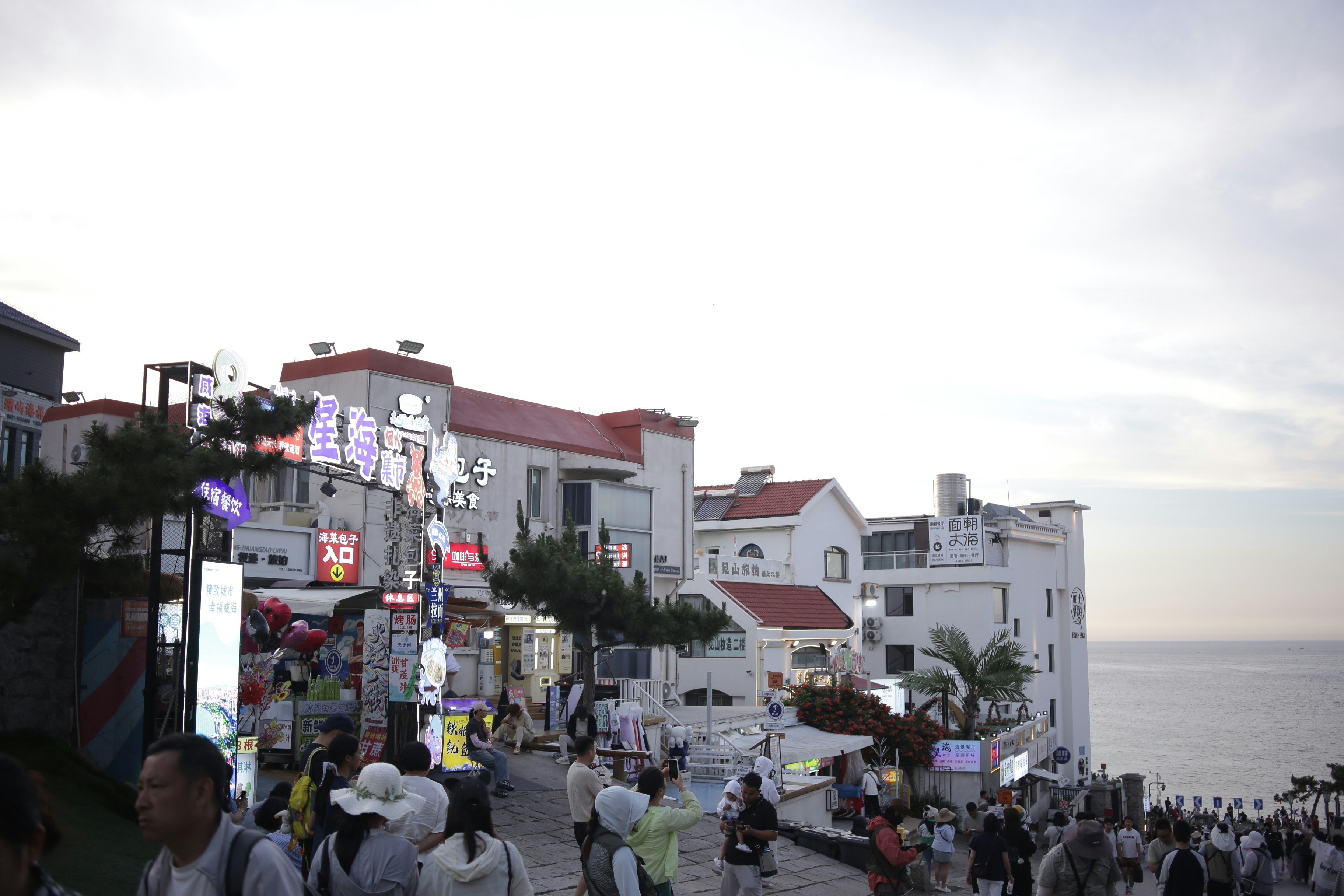 Lively seaside promenade dotted with signs and crowds at golden-hour coast