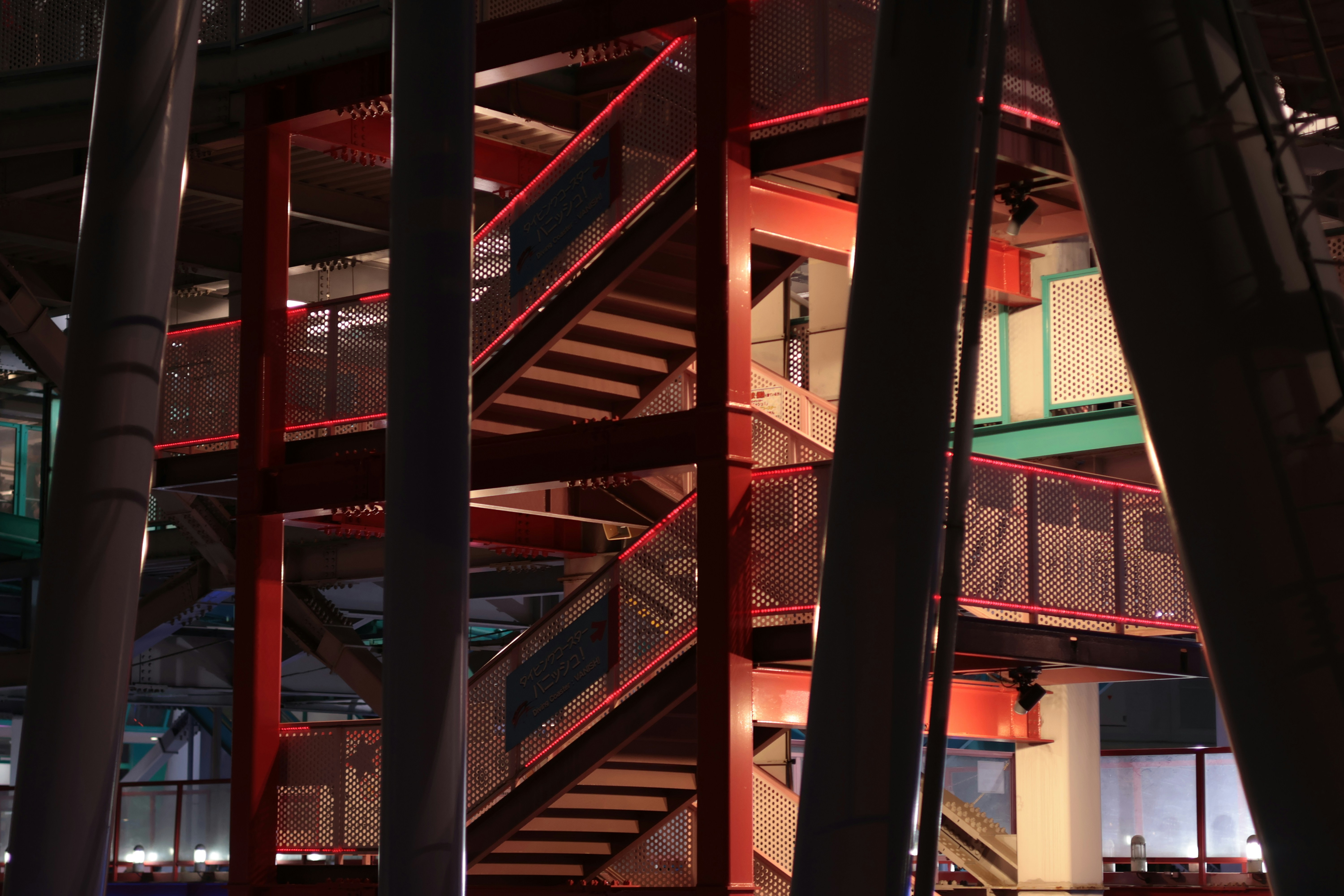 Industrial Geometry: A Staircase Network Under Red Metal Beams