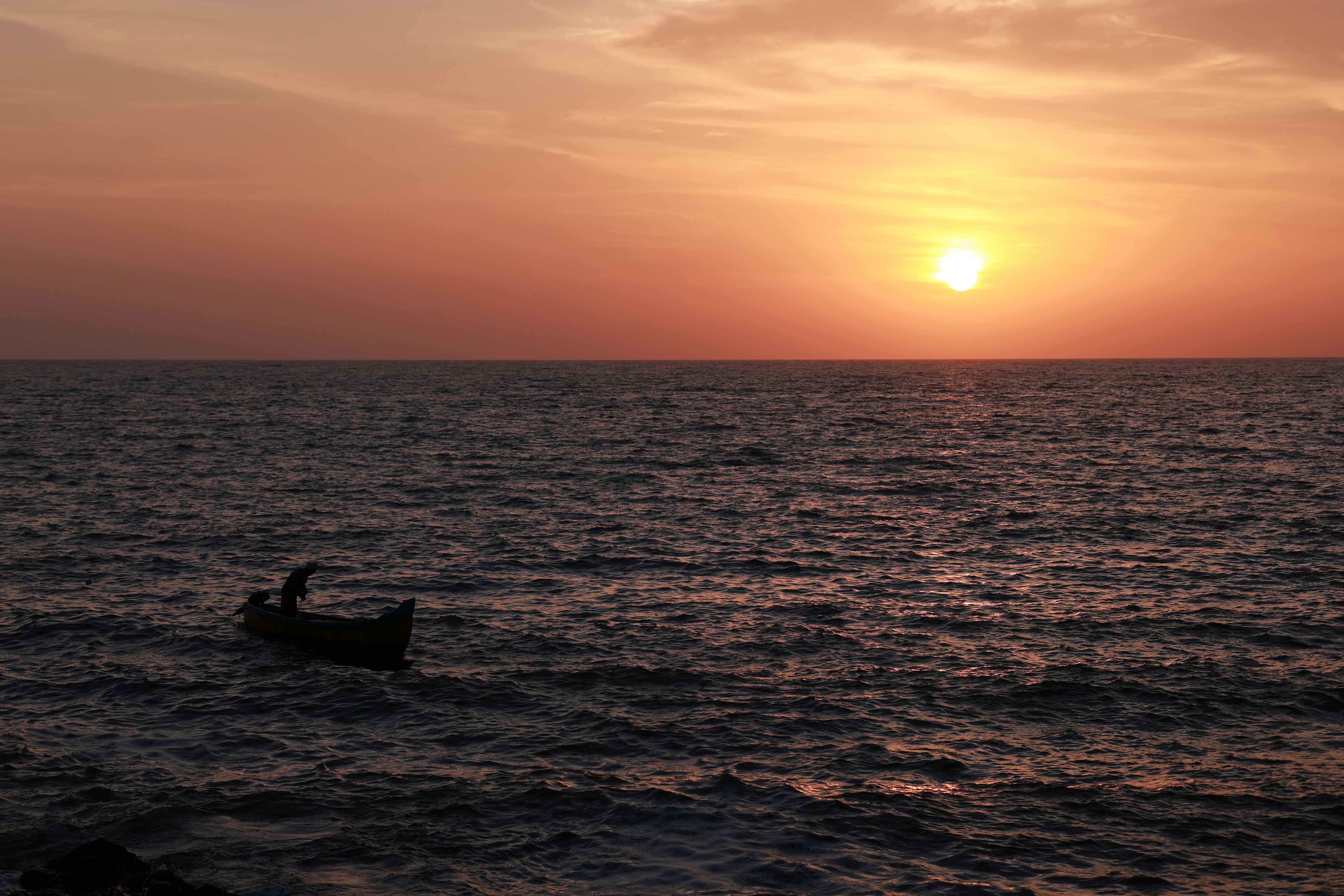 Sunlit Horizon: Lone Boat Beneath a Dusk-Glowed Sea