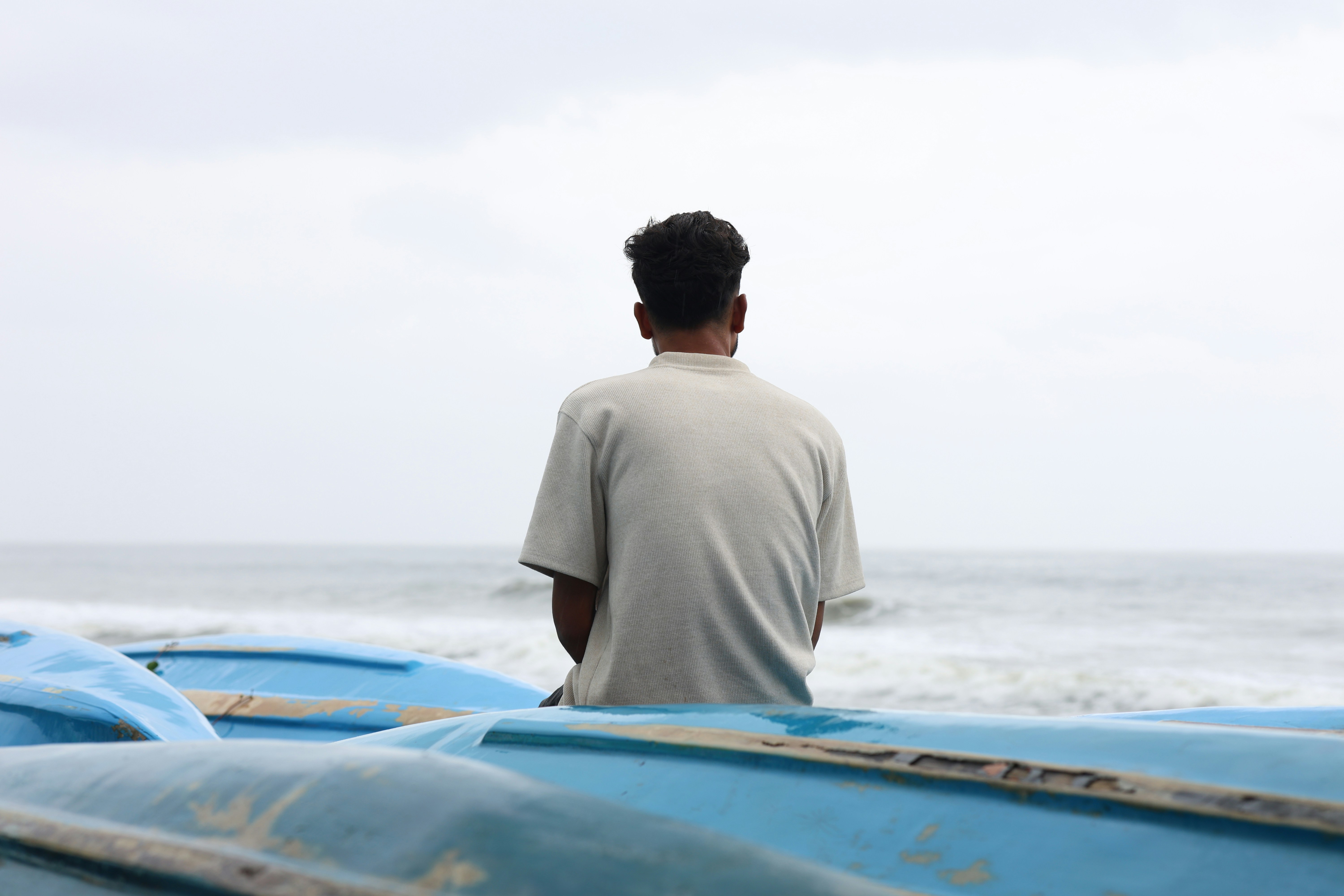 Seated by the Horizon: A Quiet Moment Among Blue Boats