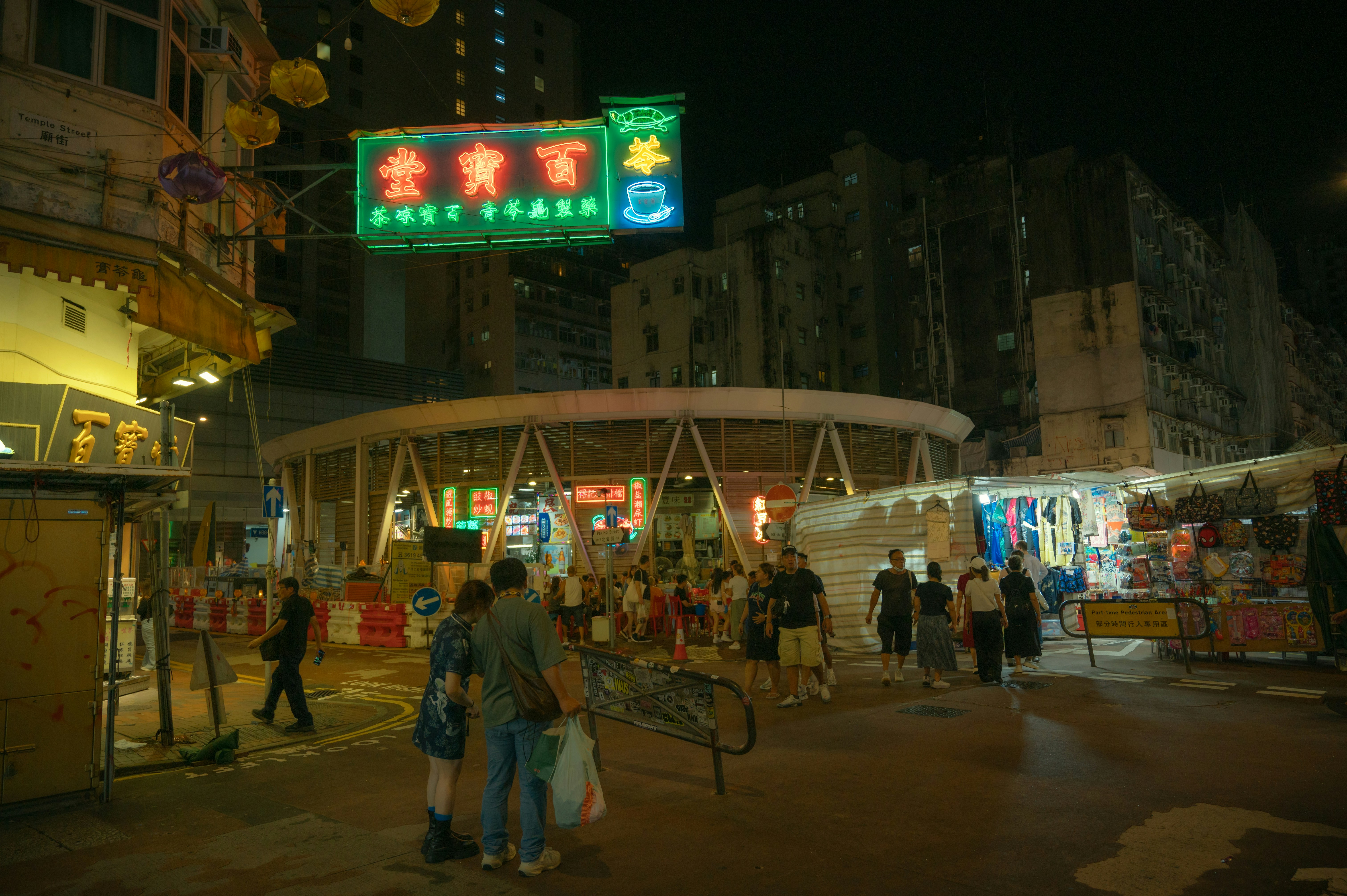 Neon Night Amid Market Lanterns: People by the Circular Entrance