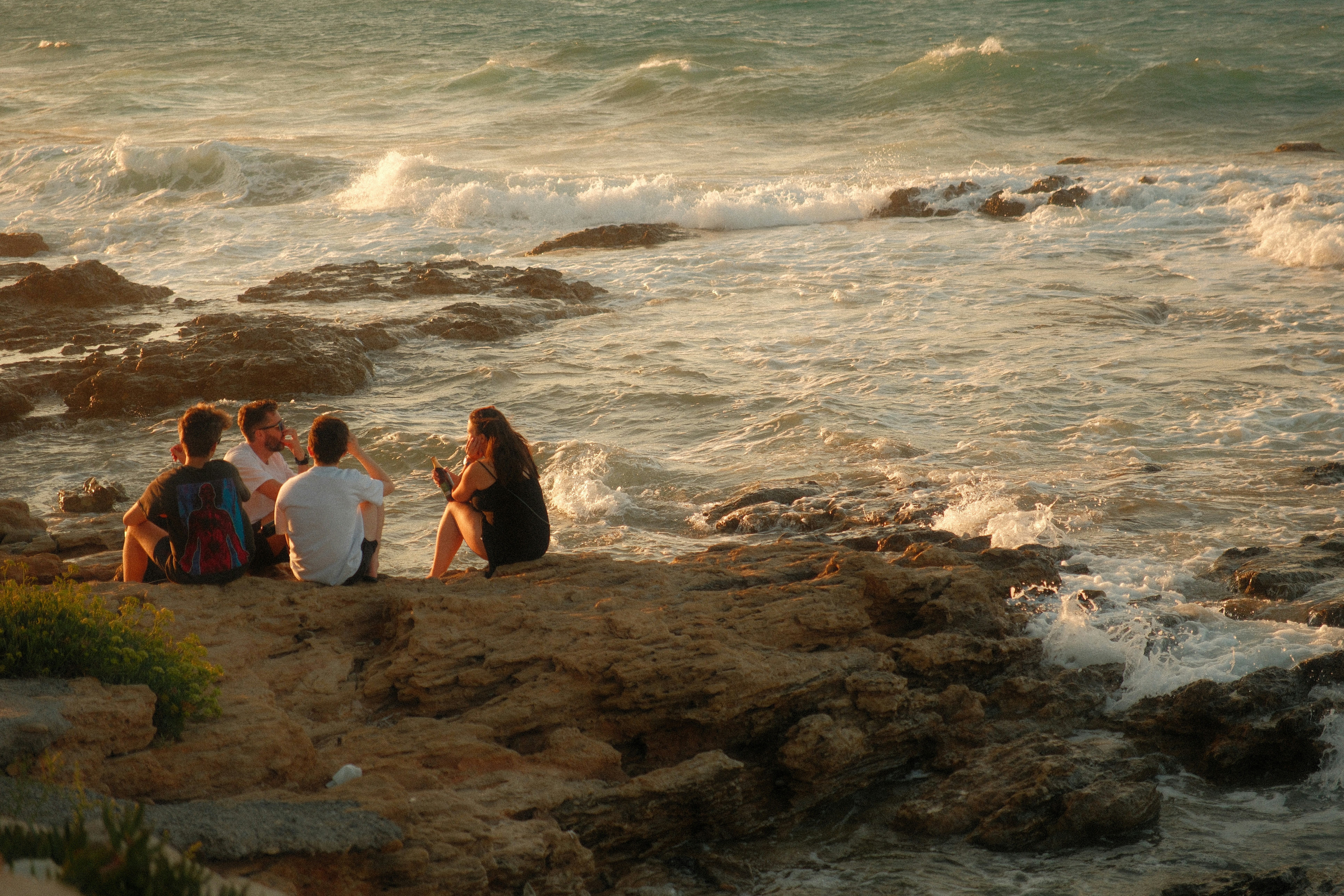 Sunlit Circle on the Rocks: Friends in Quiet Conversation by the Sea