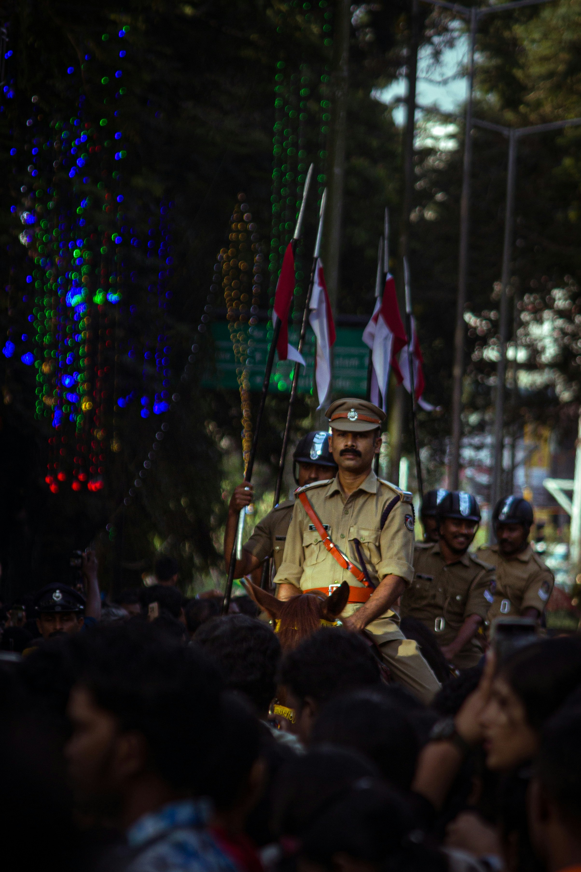 Mounted Parade: A Police Officer in Uniform Leads the Crowd Under Colorful Holiday Lights