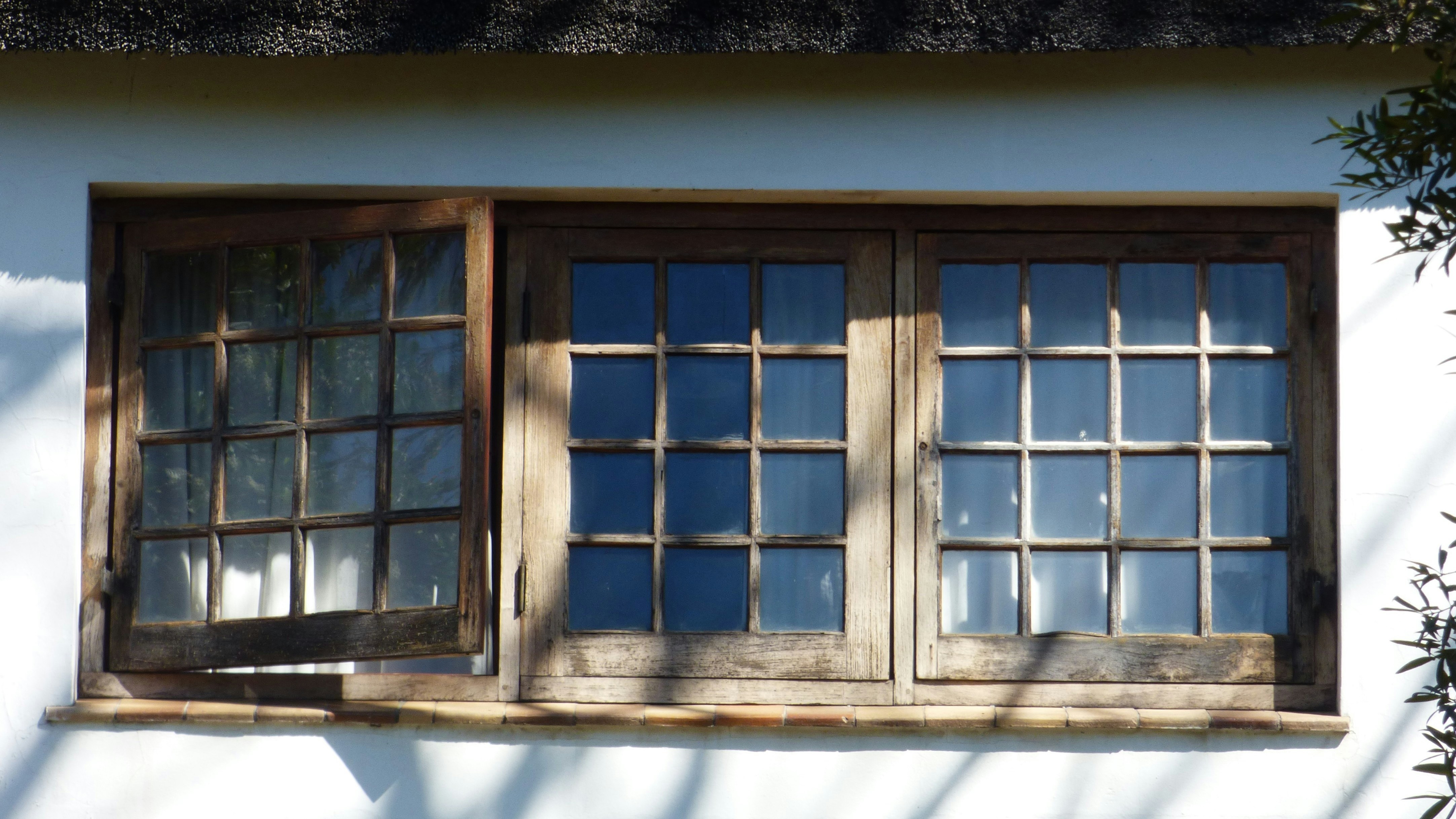Three-pane Wooden Window—Sunlit Grids Casting Shadow Patterns