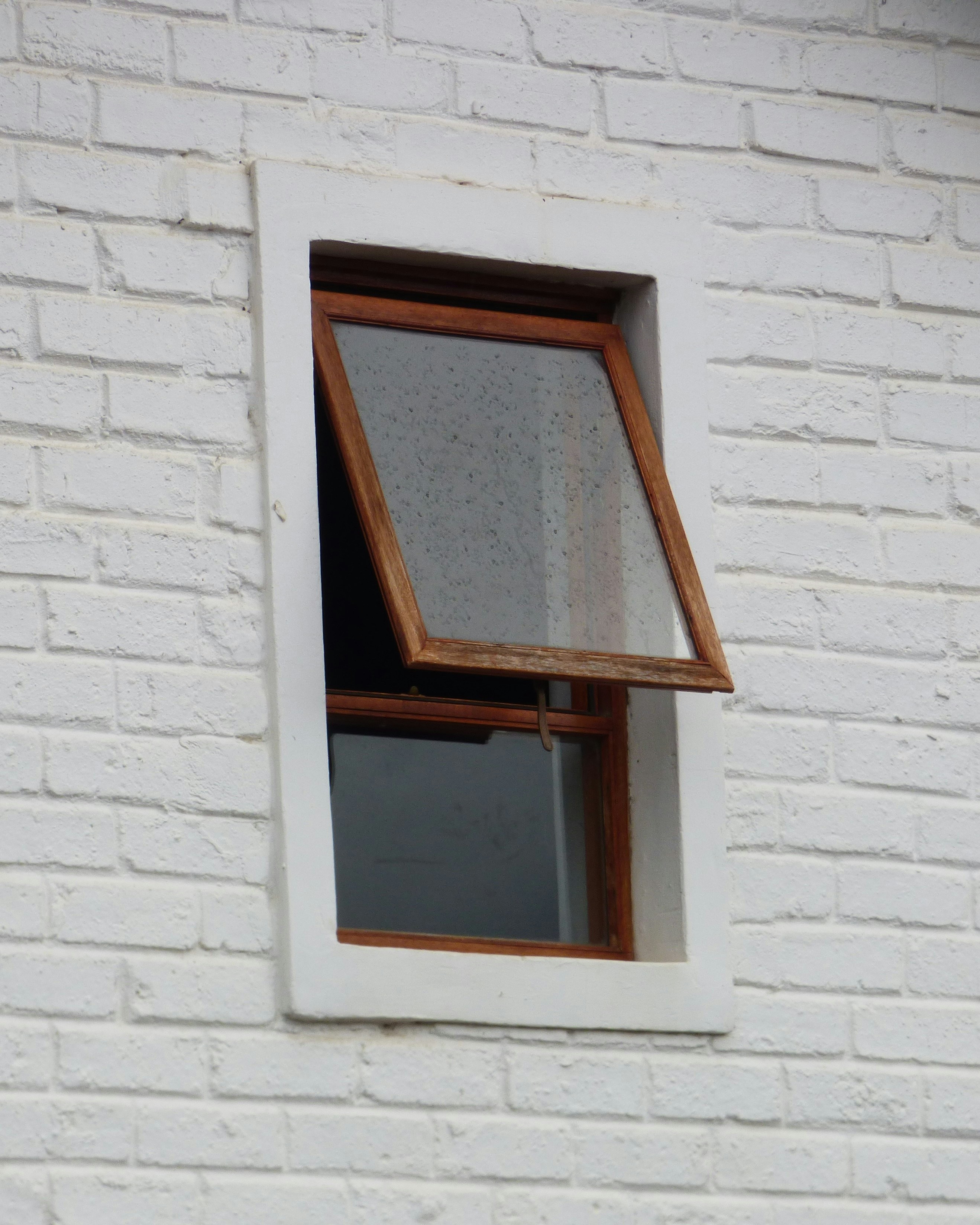 Tilted Window in a White Brick Facade
