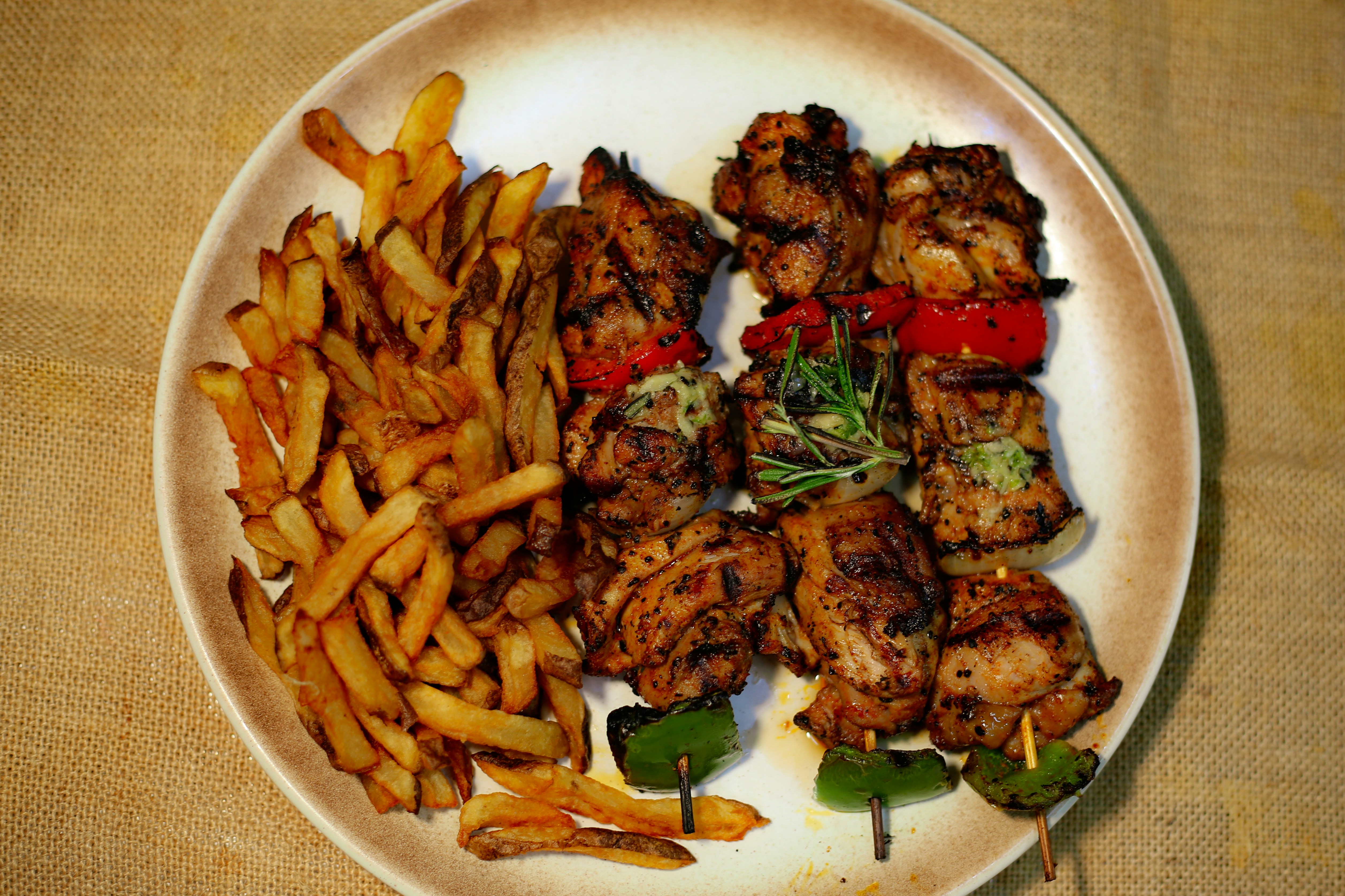Charred Skewers and Crispy Fries: A Rustic Plate of Grilled Chicken with Herbs