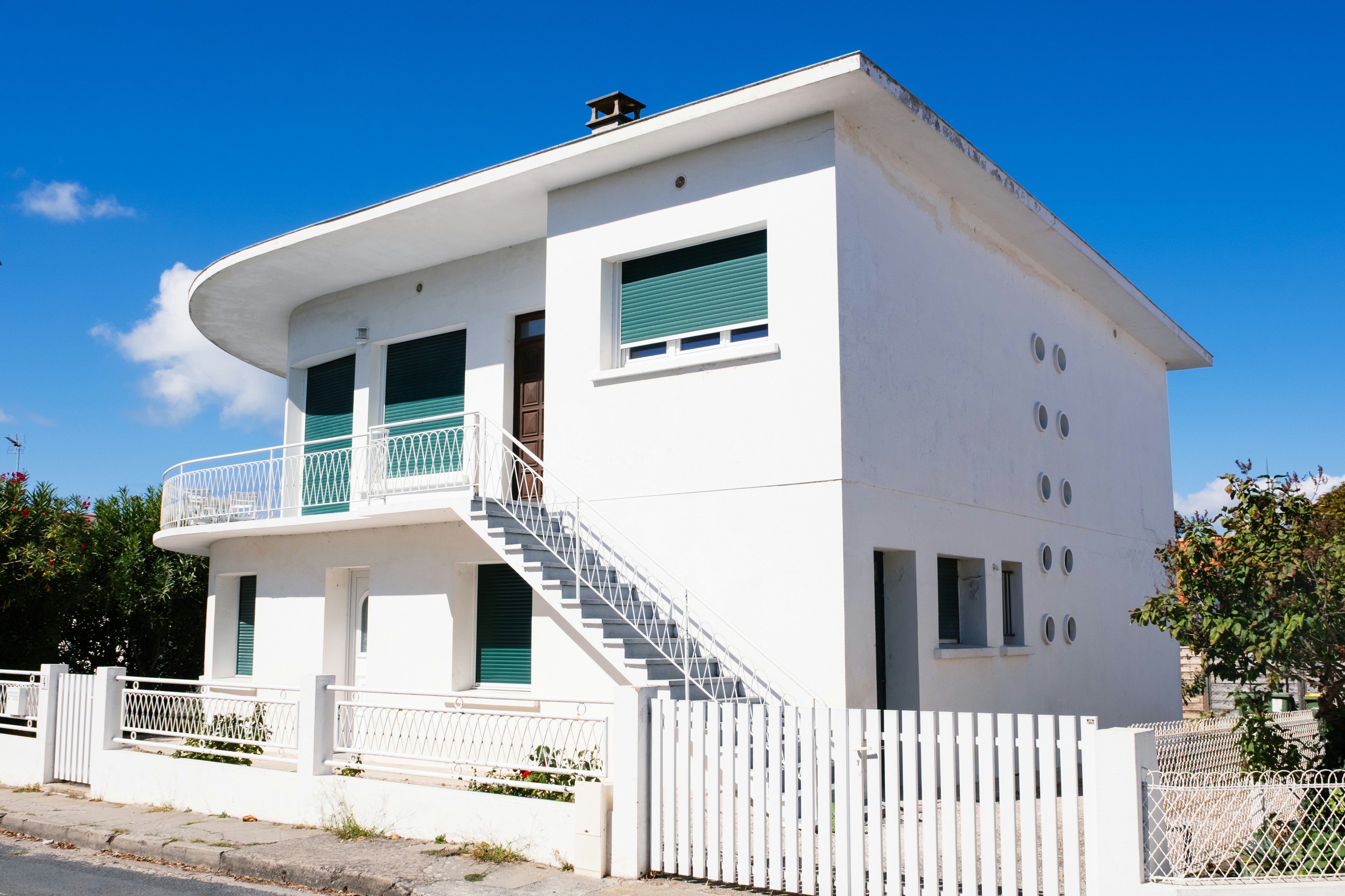White Modern House with Exterior Staircase under a Clear Blue Sky