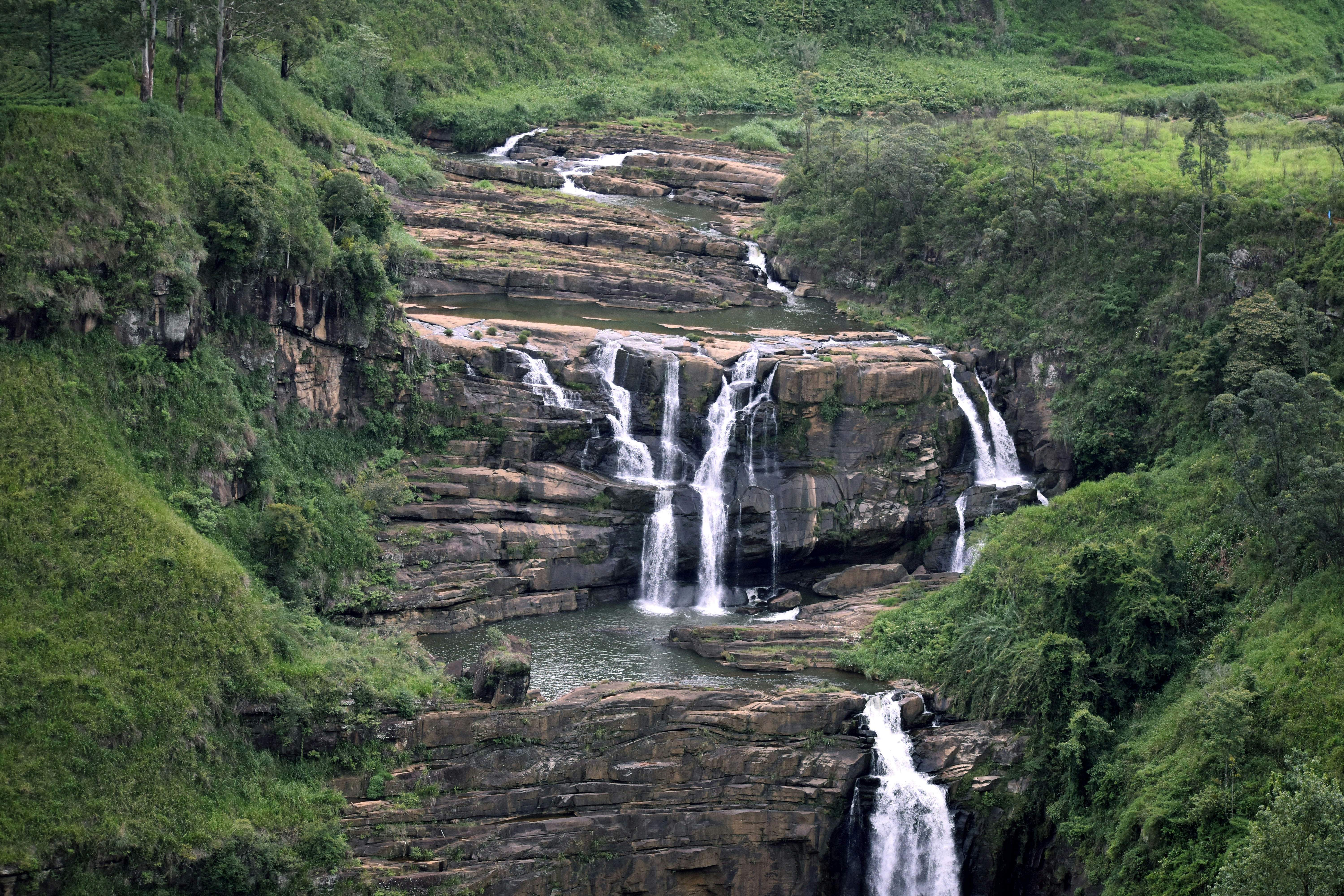 Tiered Green Majesty: Cascading Falls Across Rugged Stone