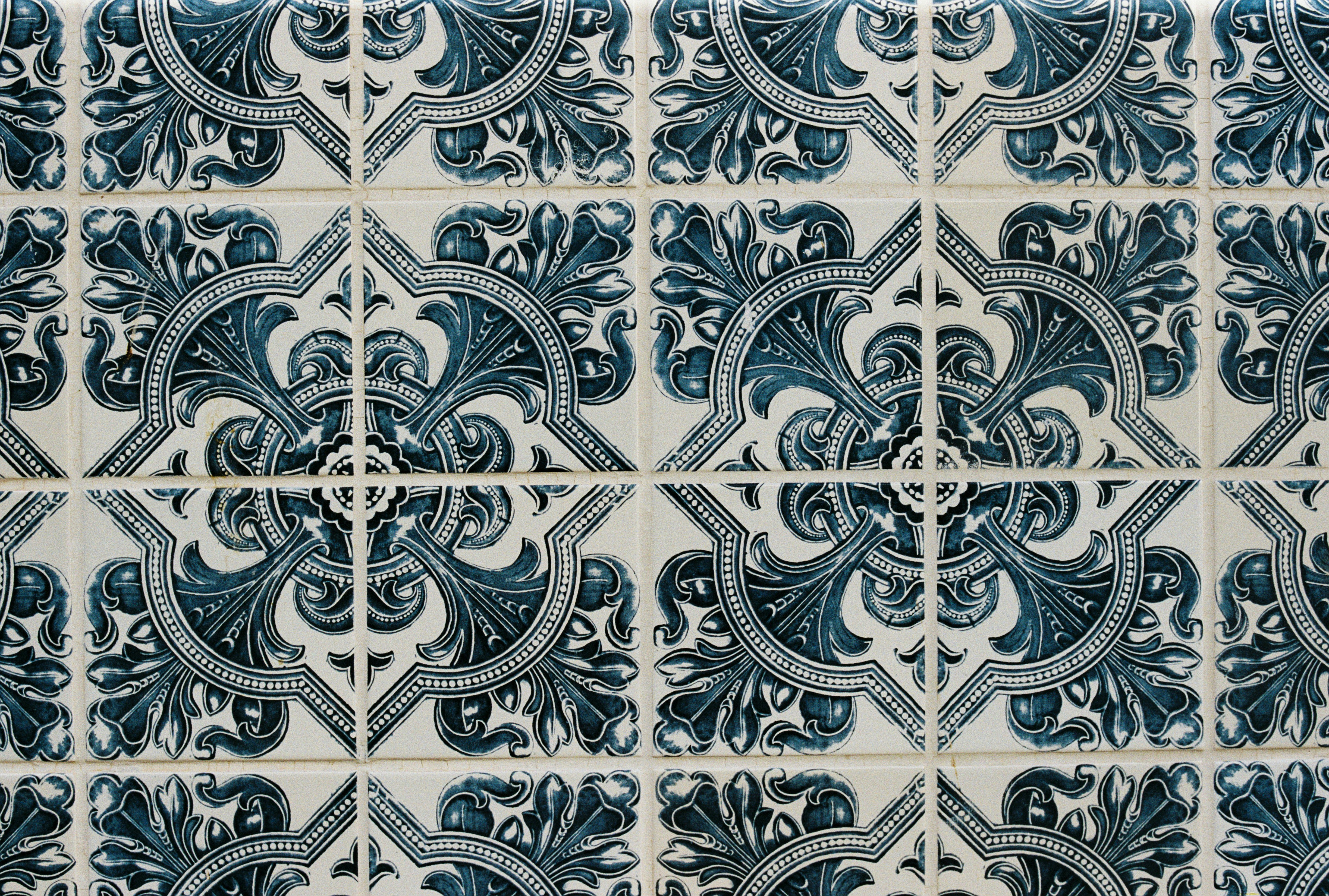 A close-up of ornate blue and white azulejo tiles forms a symmetrical repeating pattern.