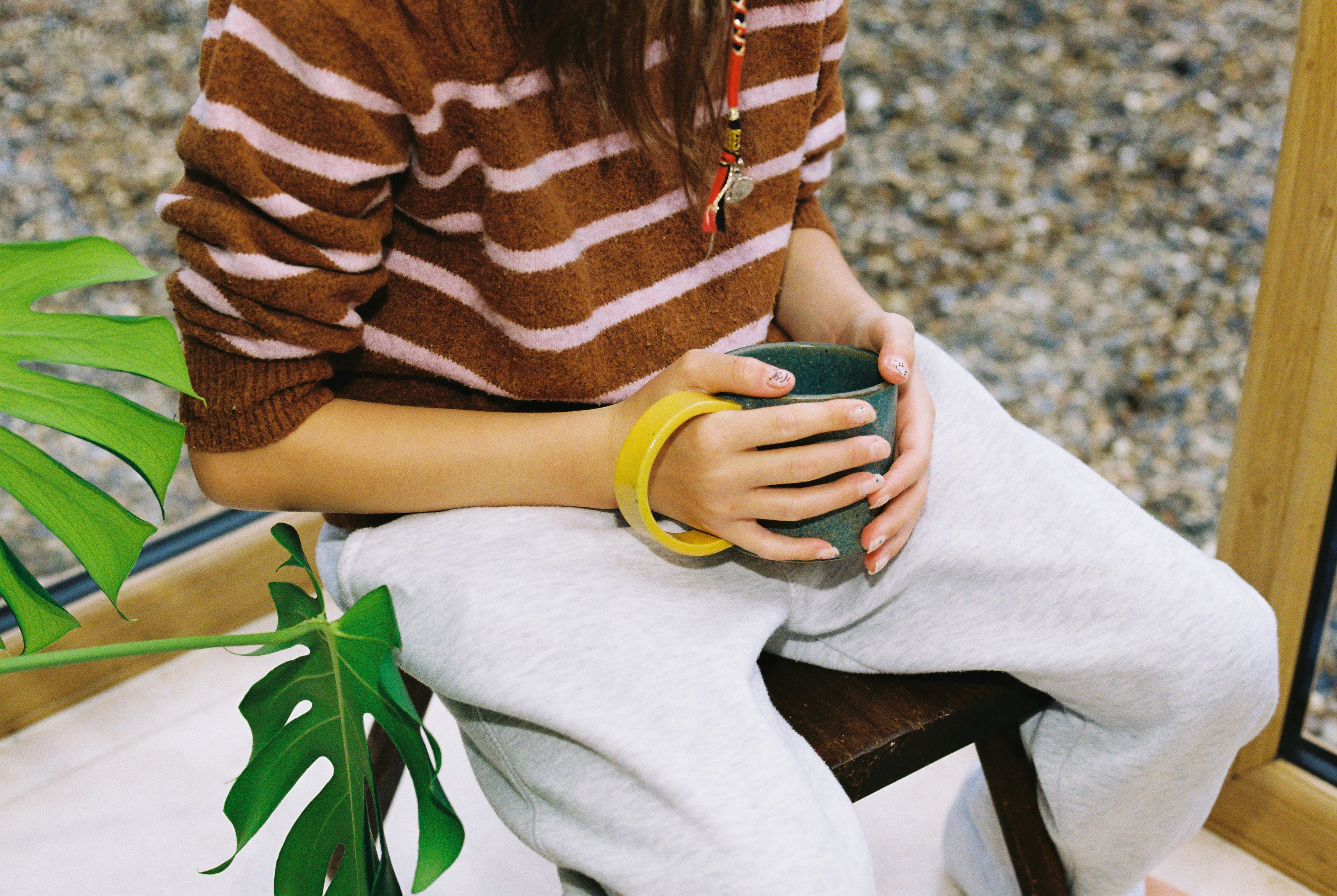 Hands around a teal mug: quiet mood on a cozy seat