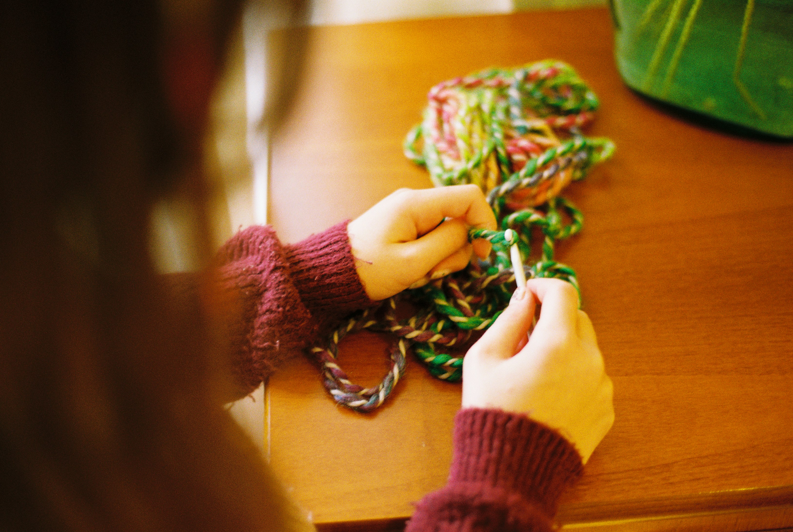 Hands at Work: Crafting Multicolored Rope on a Wooden Table