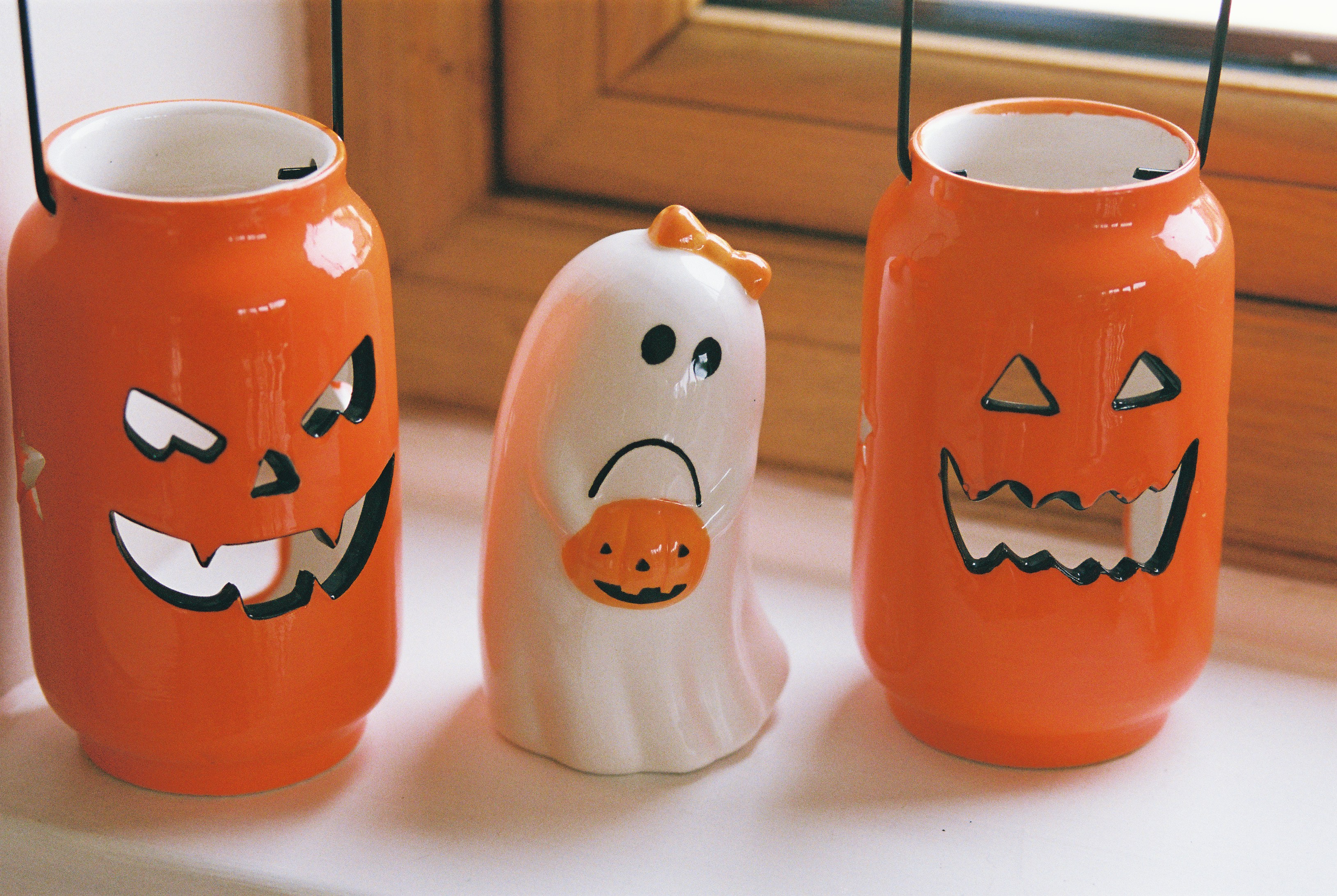 Three Jack-o’-Lanterns and a Ghostly Figurine Glow on a Windowsill