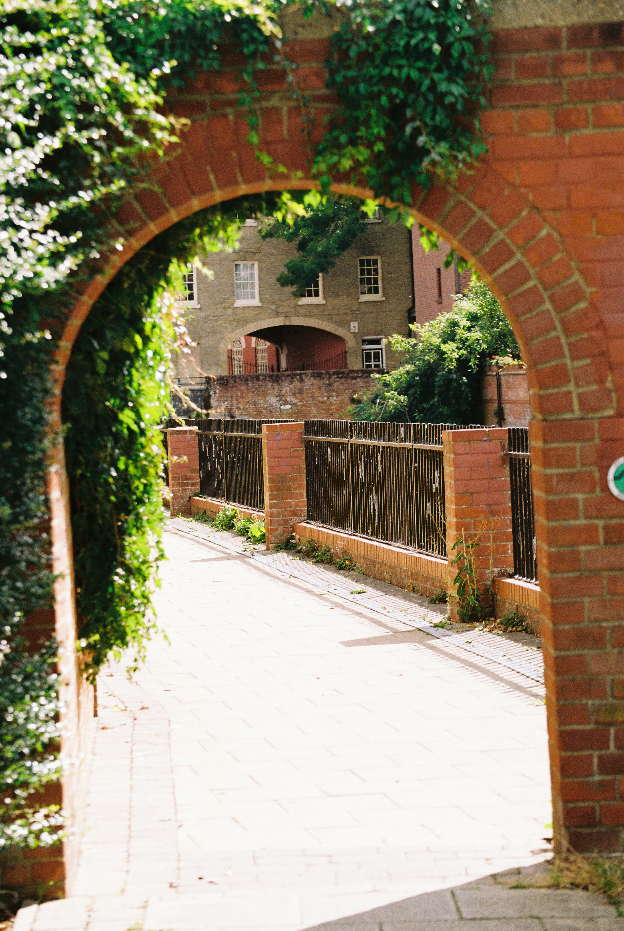 Through the Brick Arch: a sunlit walkway to a quiet courtyard
