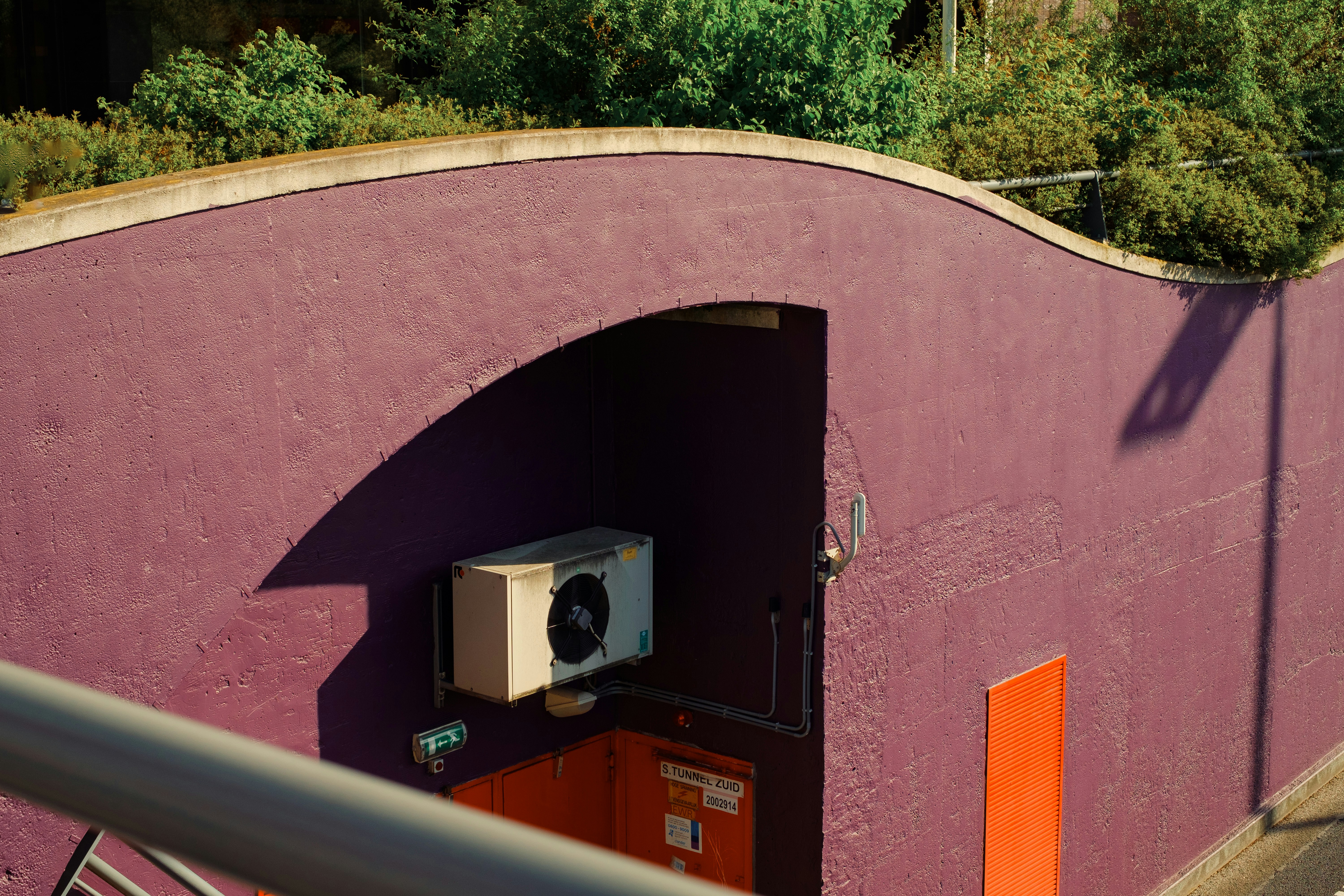 Curved Wall Quietude: A purple facade with utility in shadow