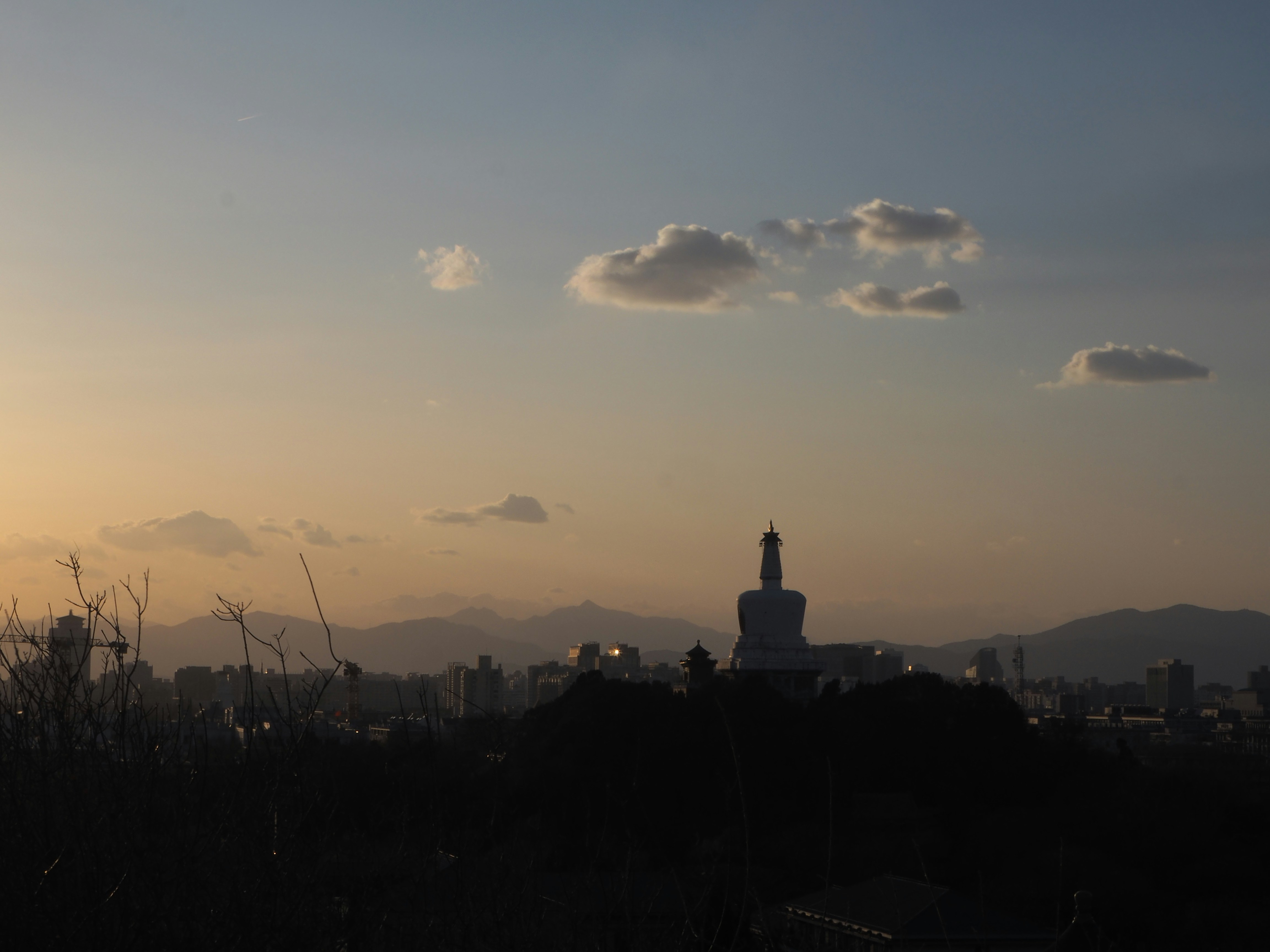 Distant Lighthouse silhouette at sunset over a quiet cityscape