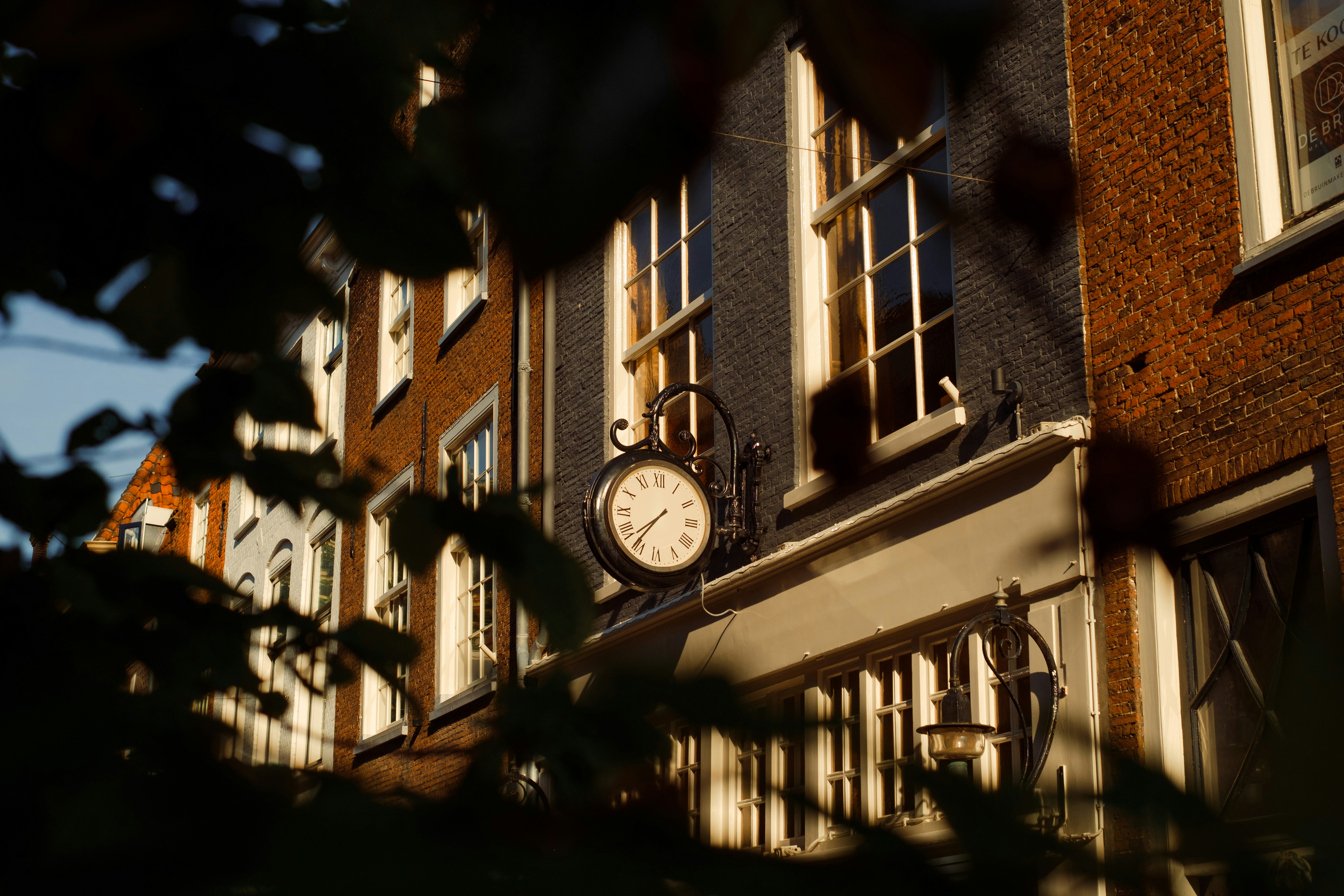 Clocktower over a quiet brick street framed by leaves