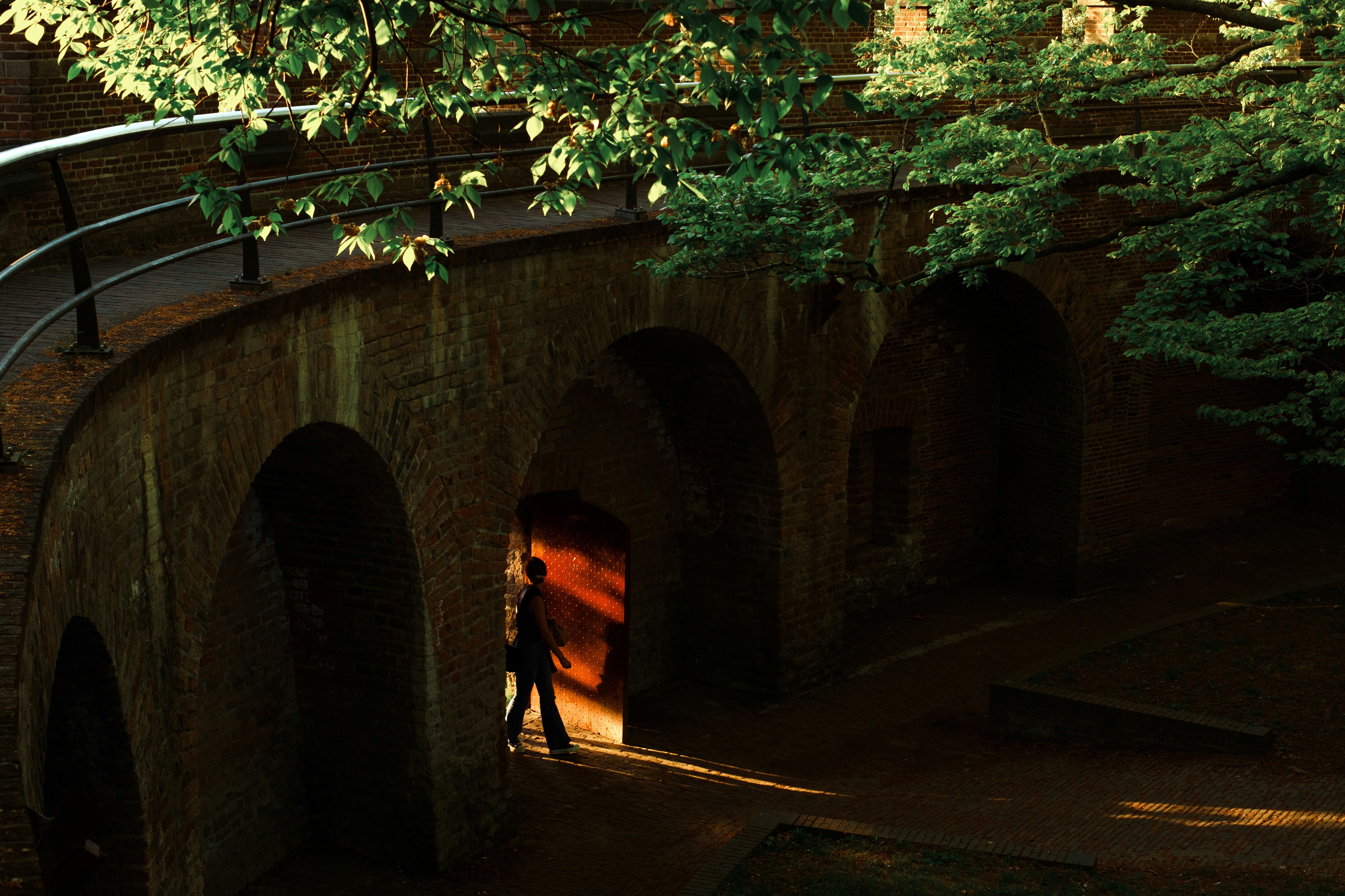 Sunlit Archway Gate: A Solitary Figure Steps Into Warm Light