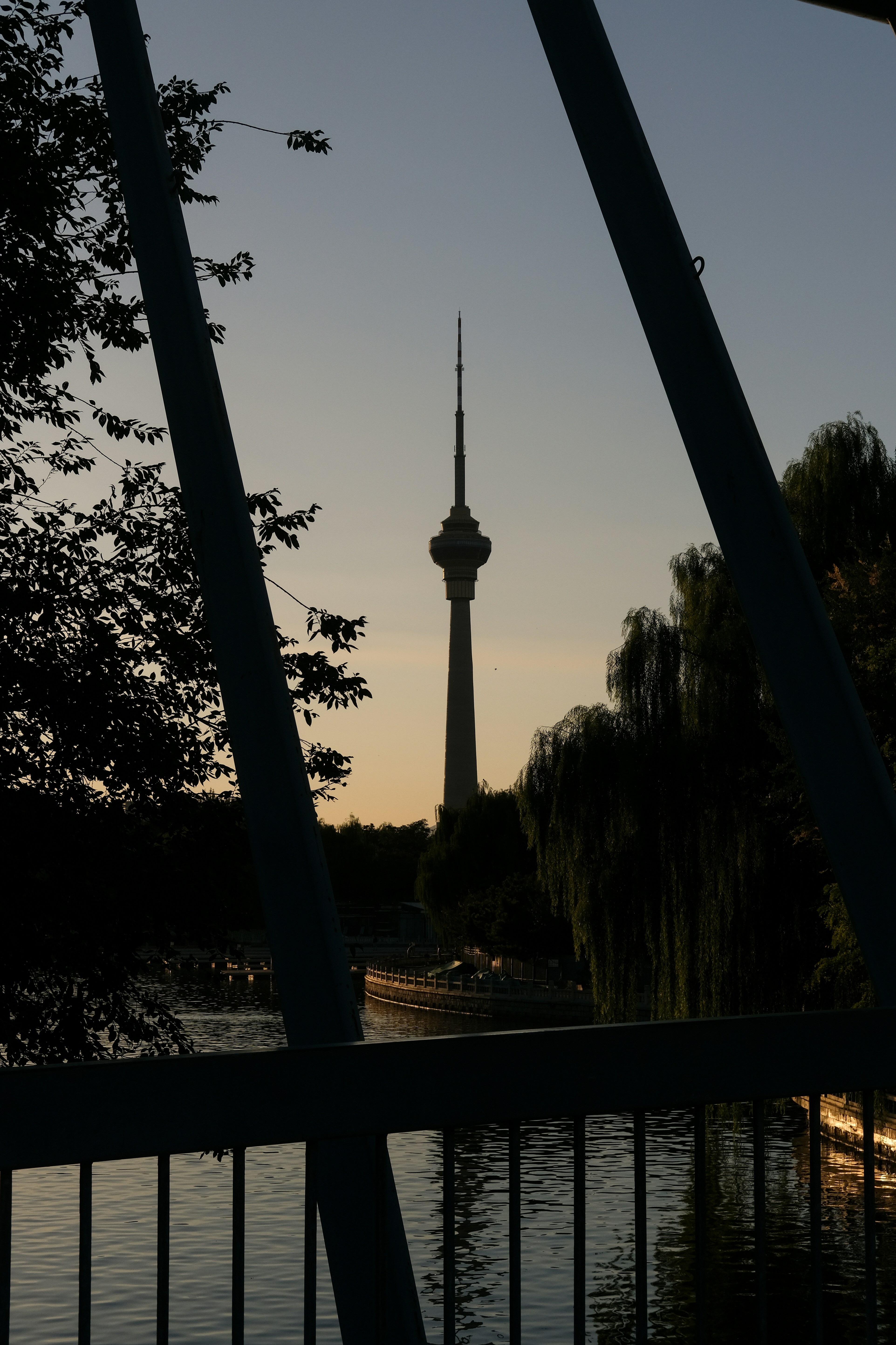 Silhouette Over the River: A Towered Skyline Framed by Bridge Beams at Sunset