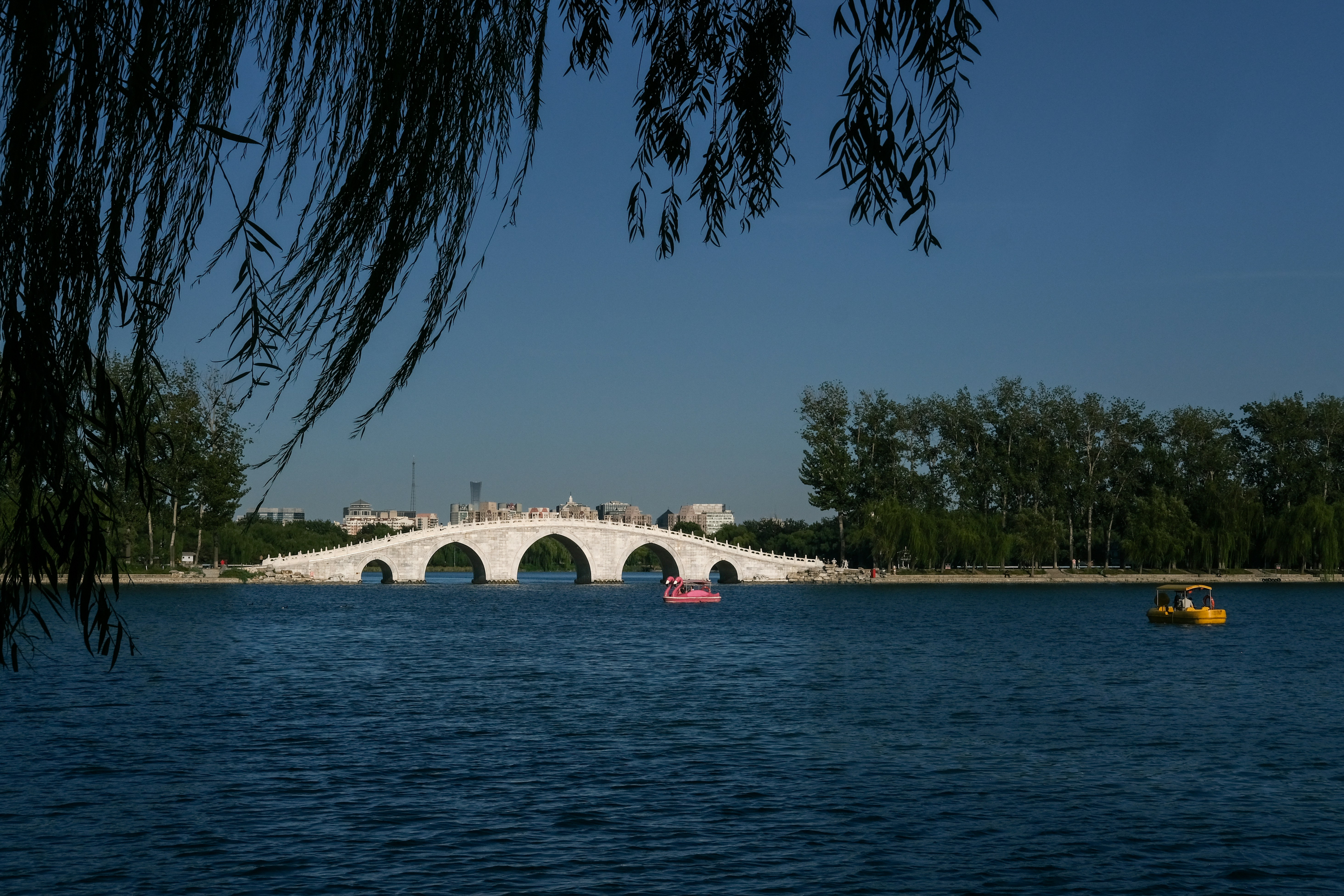 Stone Arches across the tranquil lake under a willow-draped canopy