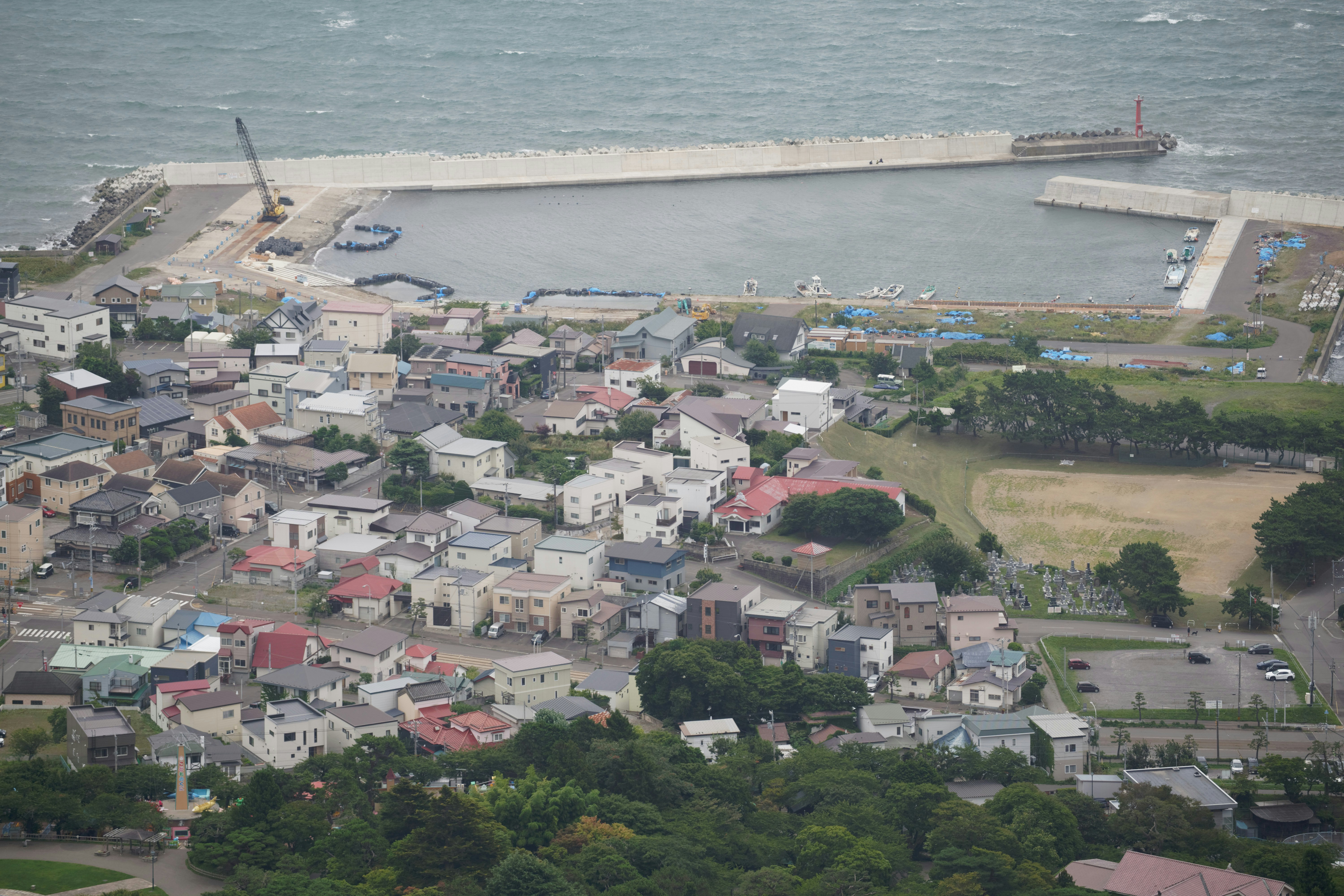 Harbor Edge Village: Aerial Tapestry of Boats, Breakwater, and Rooftops