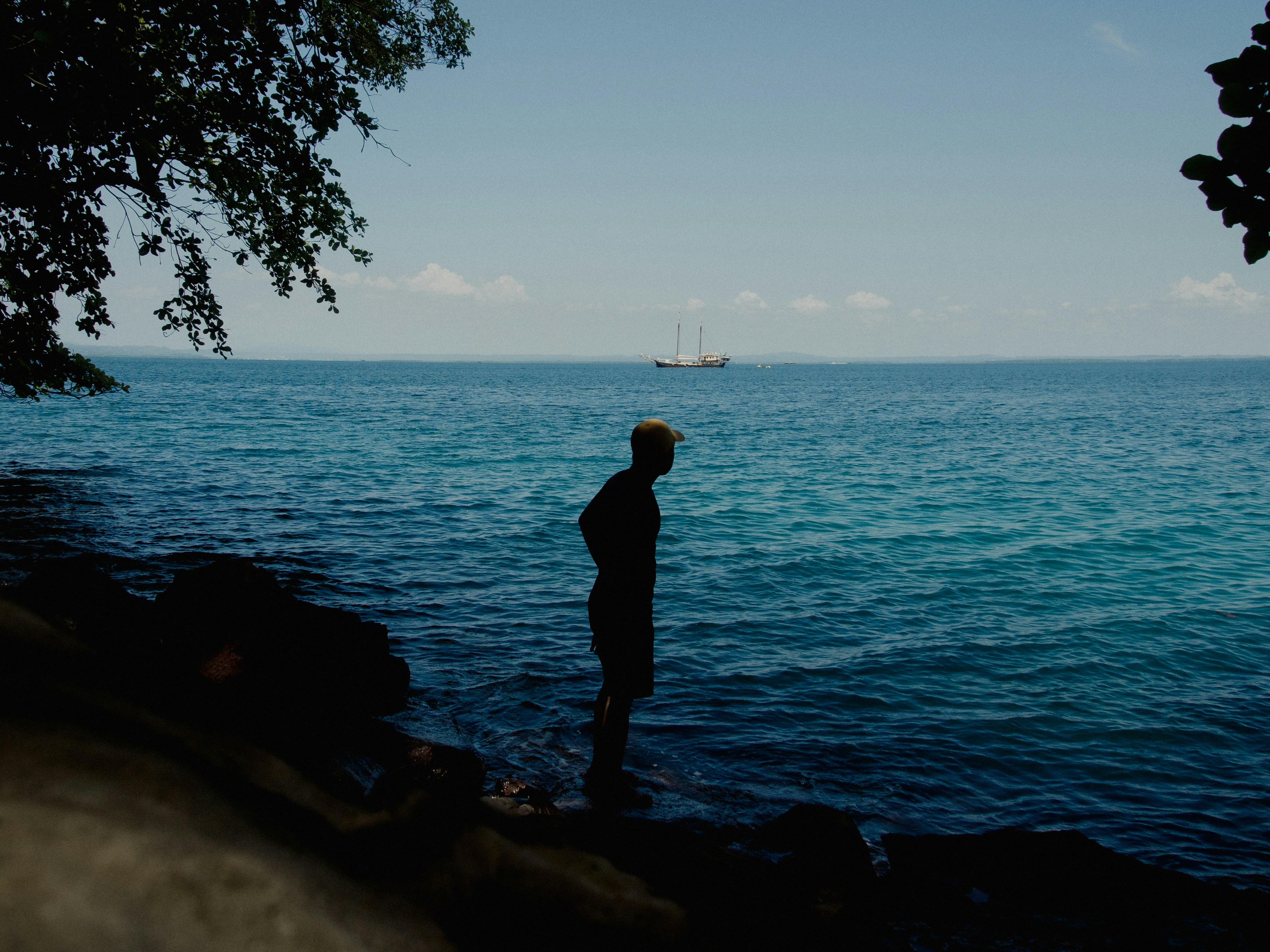 Standing at the edge of the world, a silhouette against the endless ocean expanse.