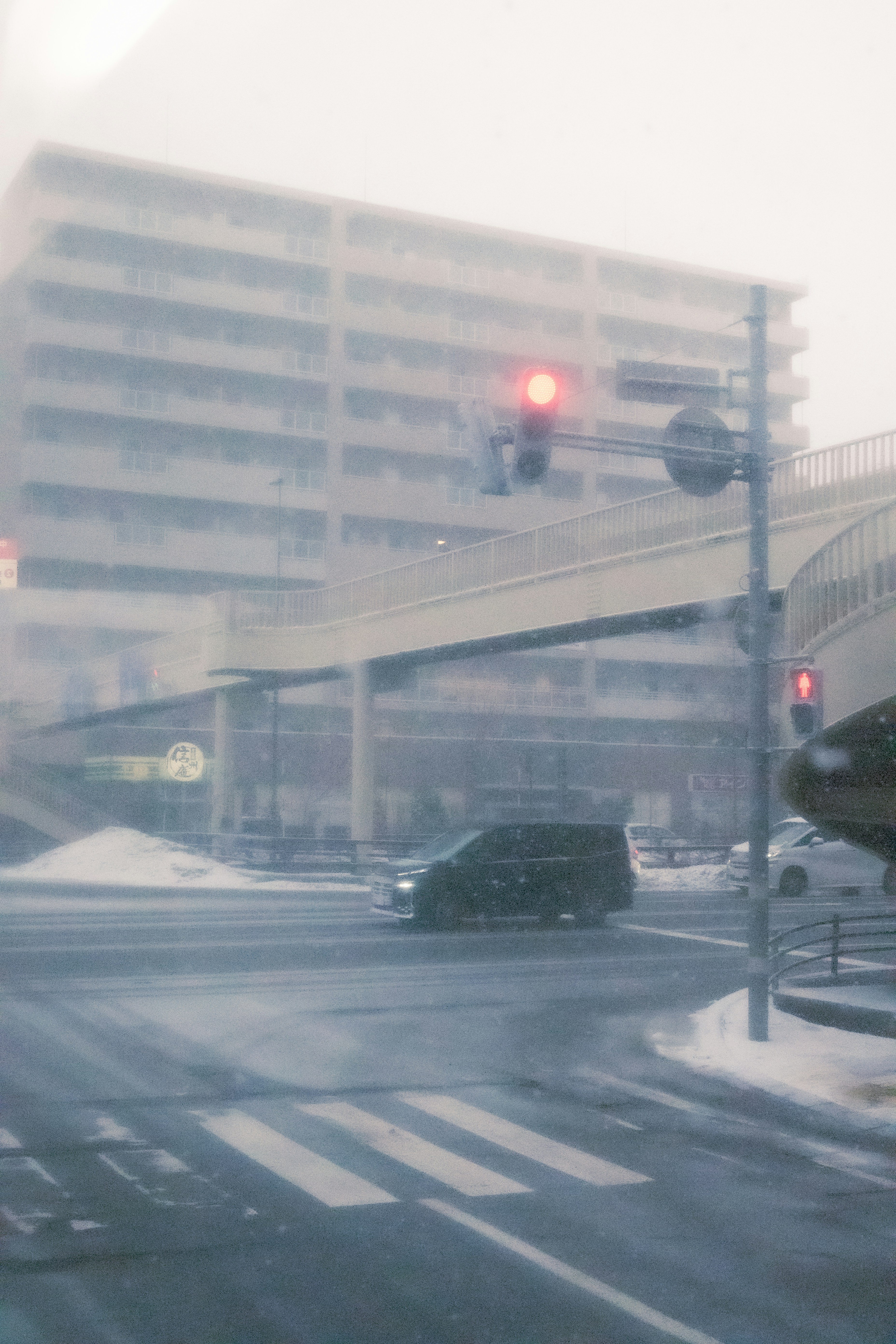 Red Signal in a Quiet City Intersection Amid Light Snow